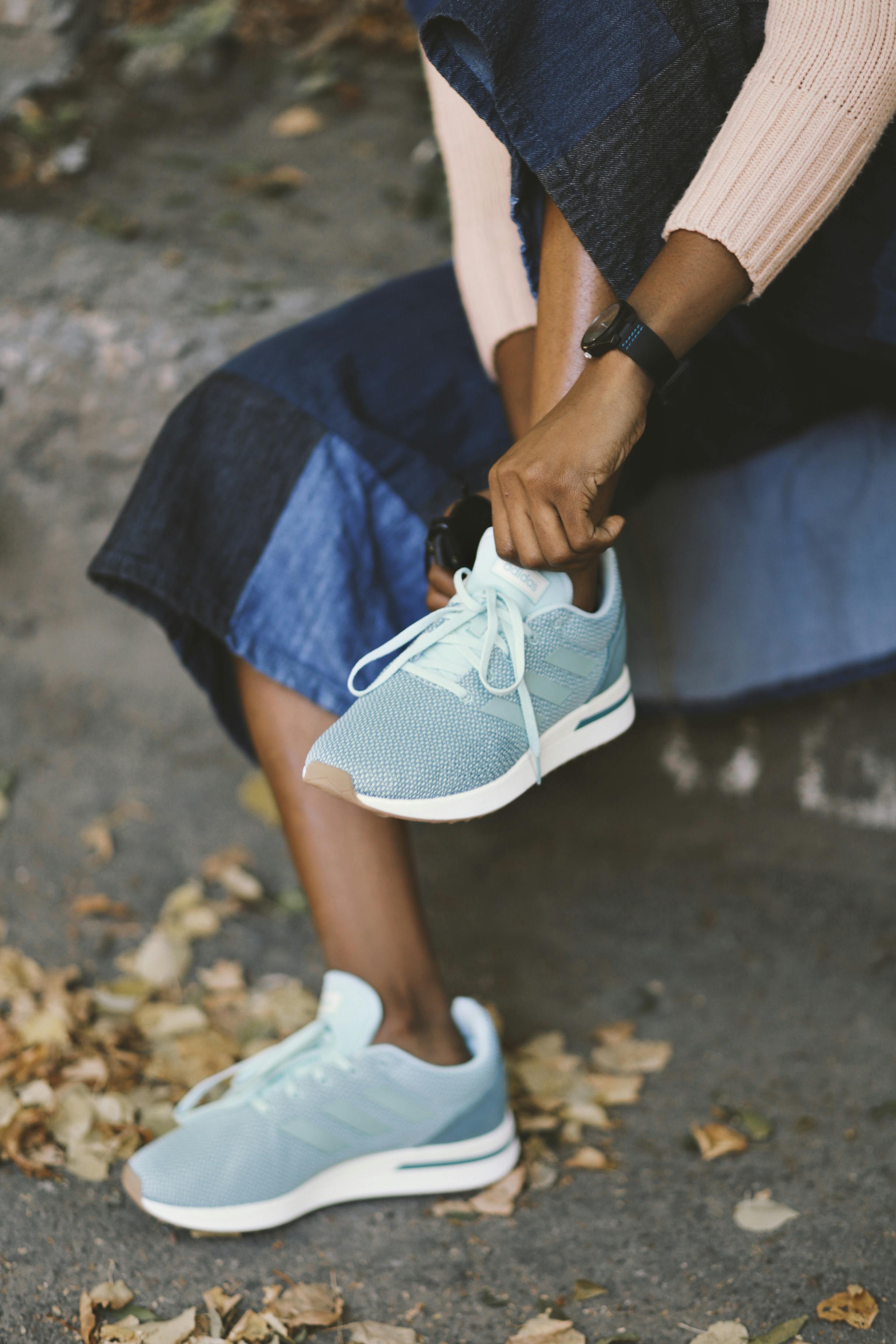 Close-up of a Girl Sitting on a Curb and Typing Her Shoe · Free Stock Photo