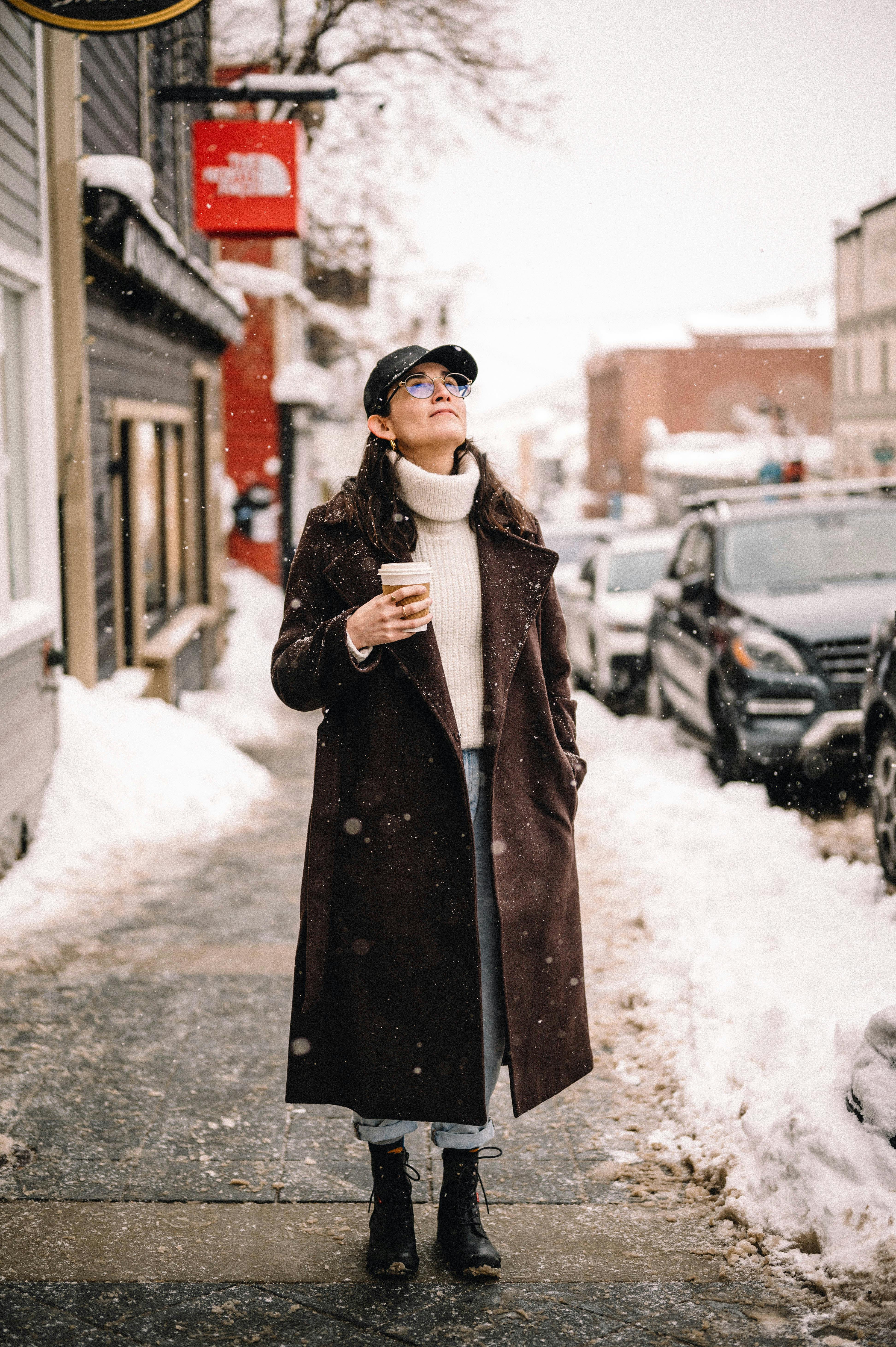 Passerby in a Brown Coat with a Disposable Cup of Coffee Looking at the ...