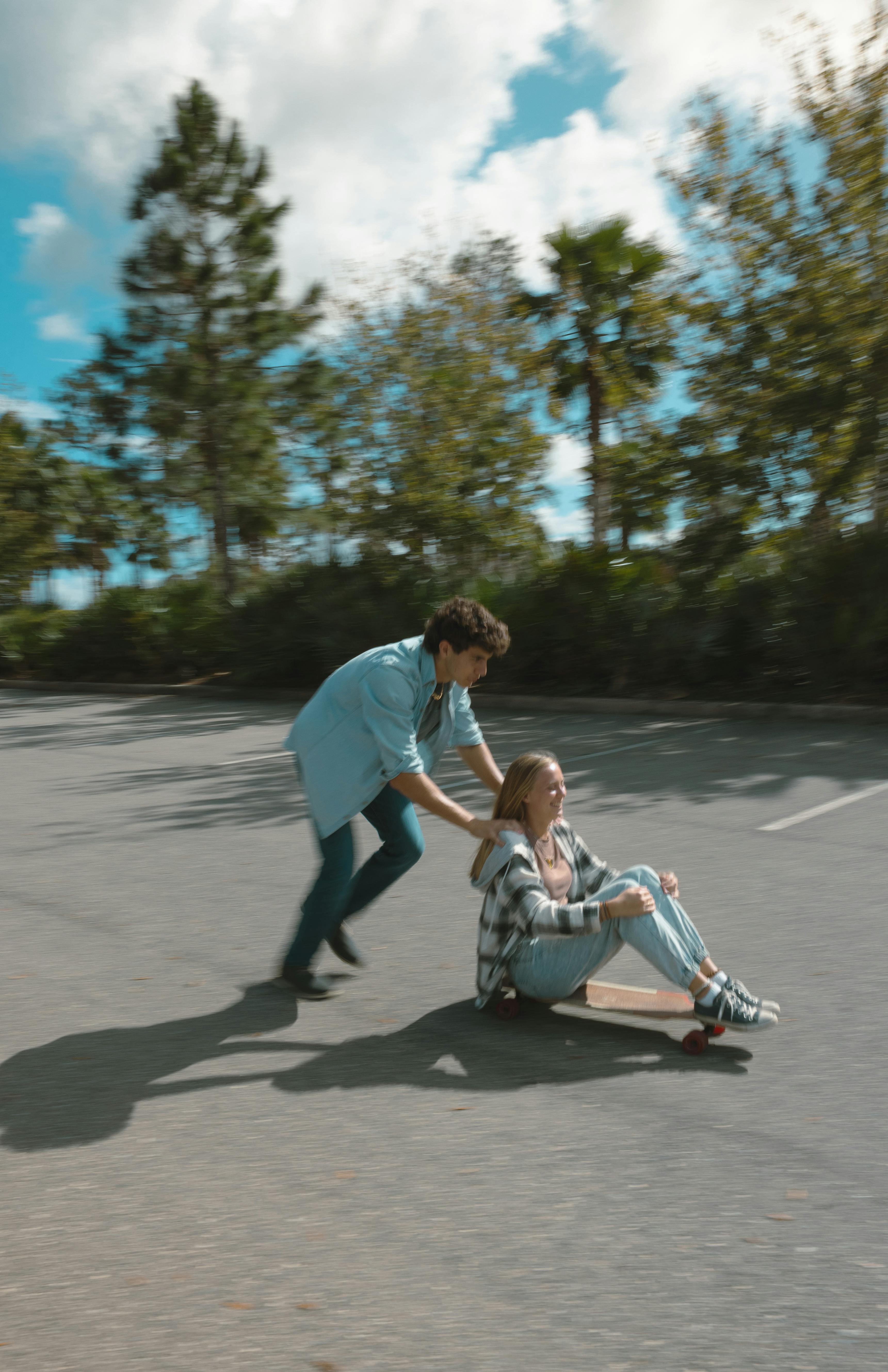 Woman on Skateboard Pushed by Man · Free Stock Photo