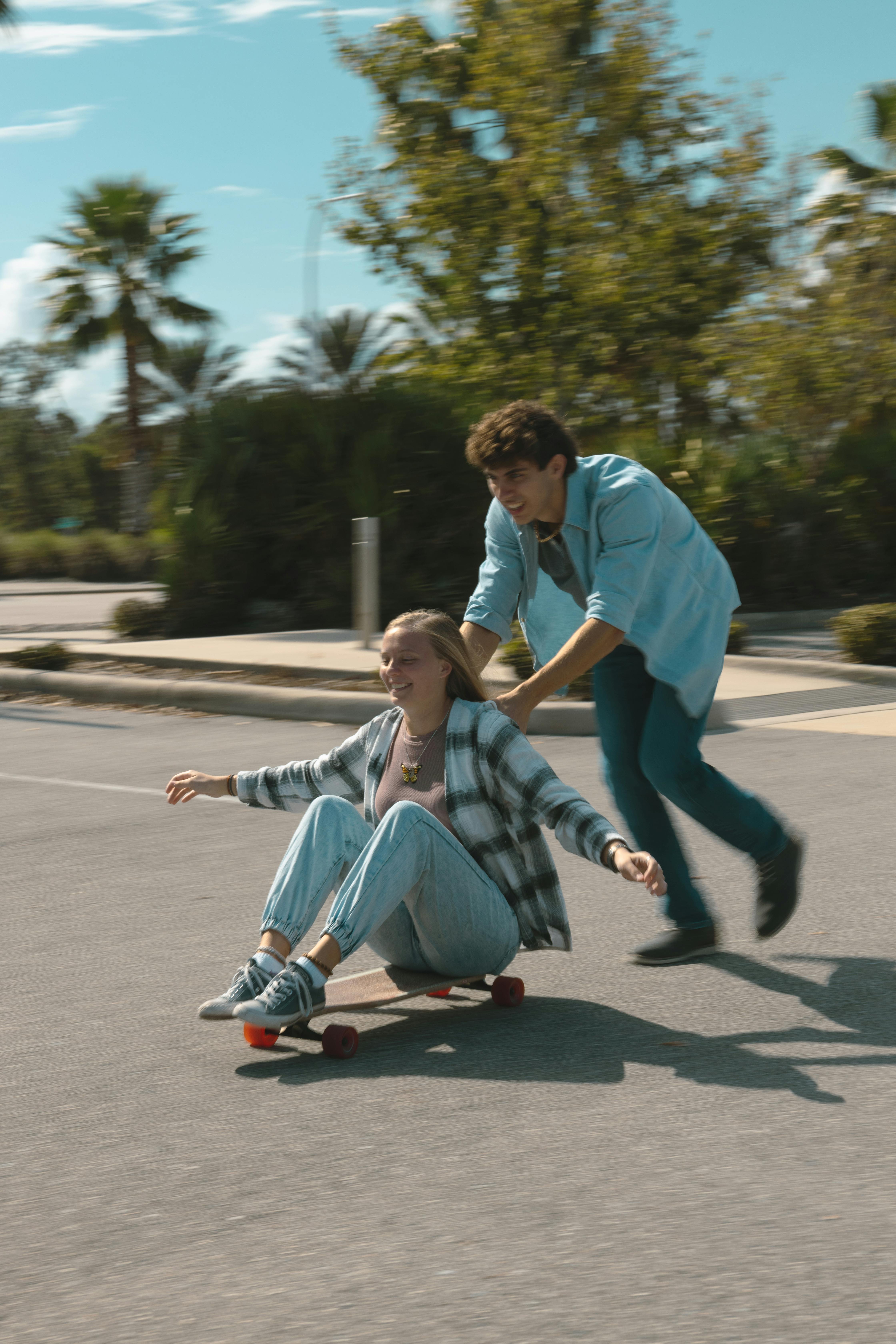 Man Pushing a Woman Sitting on a Skateboard · Free Stock Photo