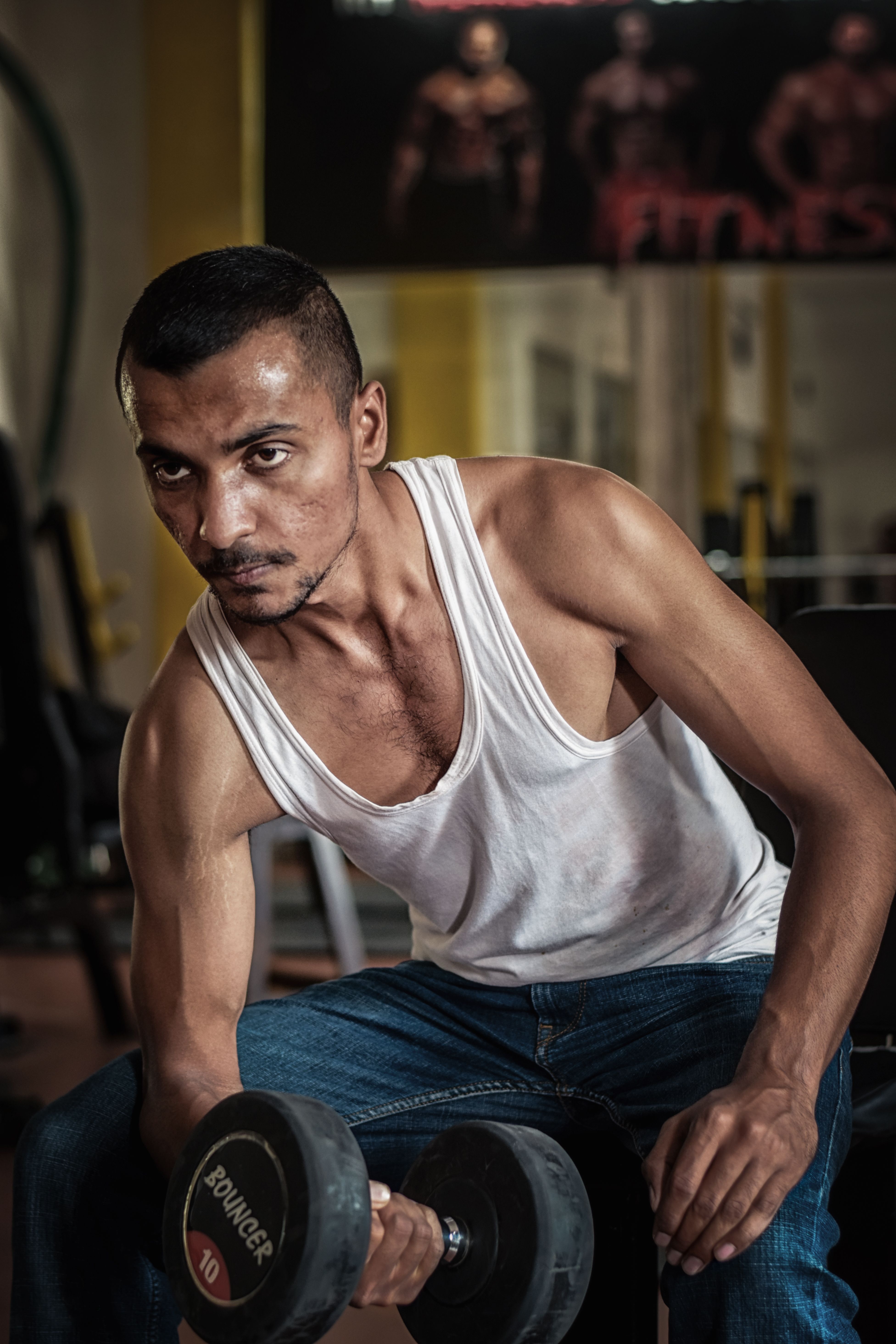 A man in a gym posing with two dumbbells · Free Stock Photo
