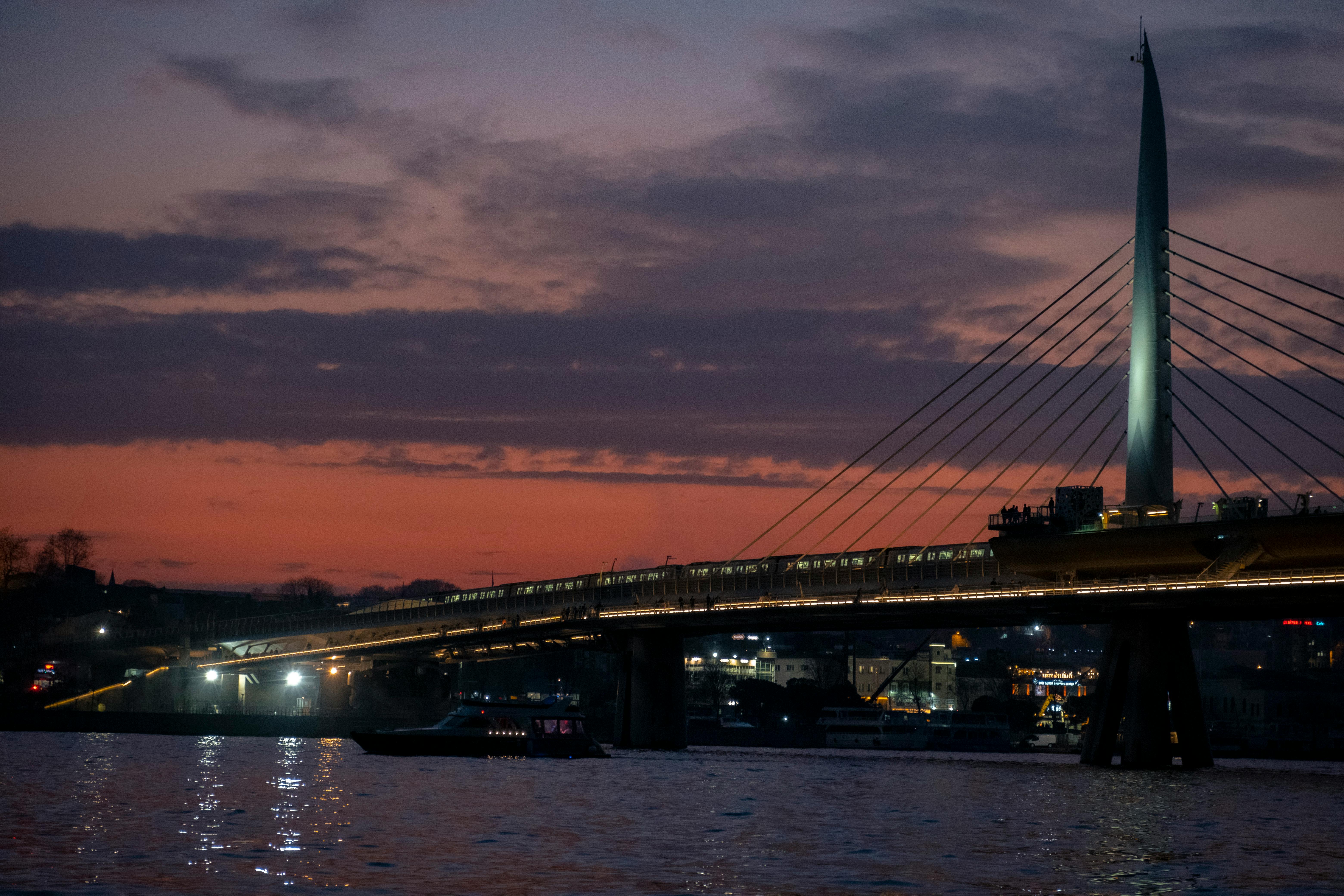 Illuminated Suspension Bridge above Water on Sunset · Free Stock Photo