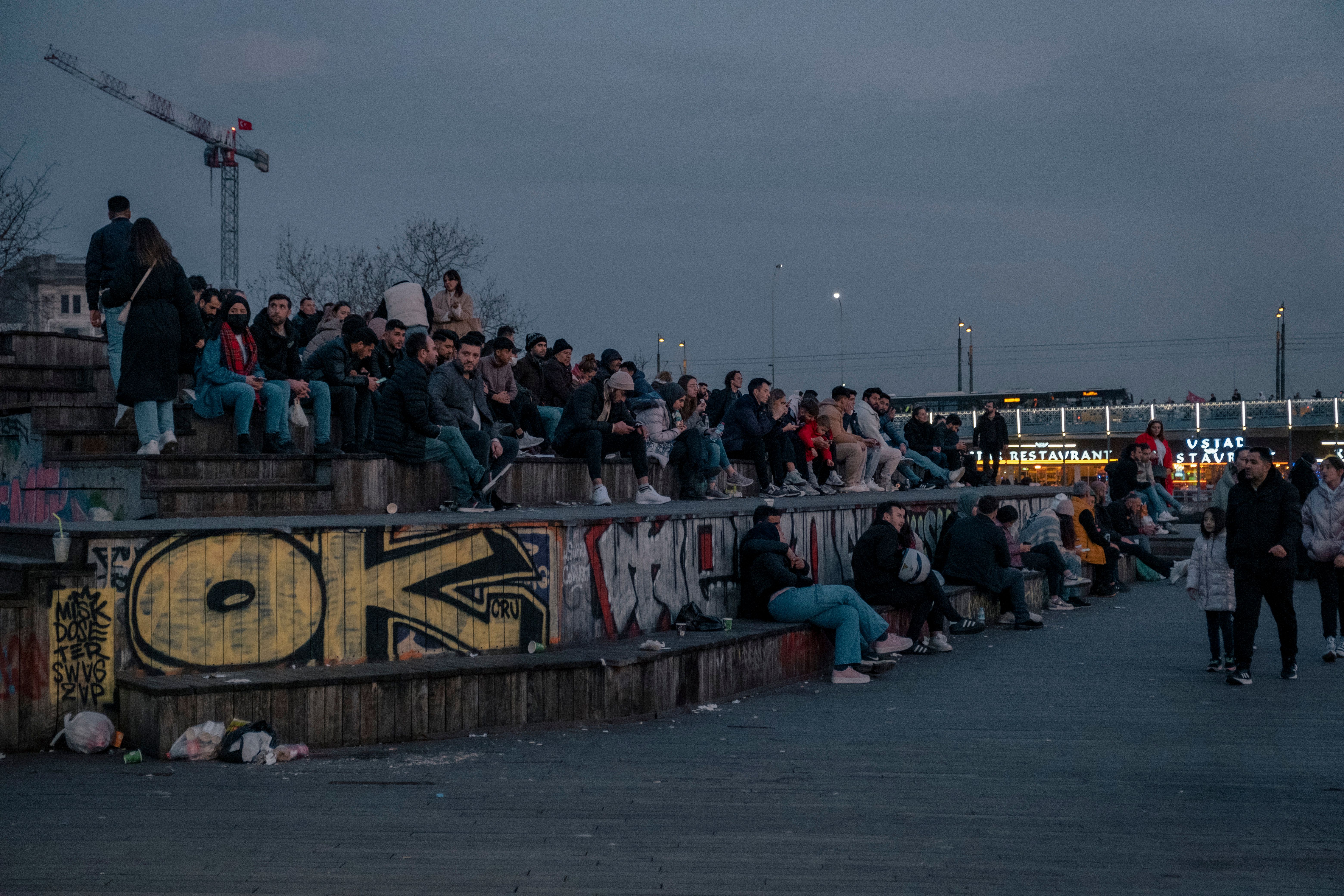 Crowd of People Sitting Outdoors at Dusk · Free Stock Photo