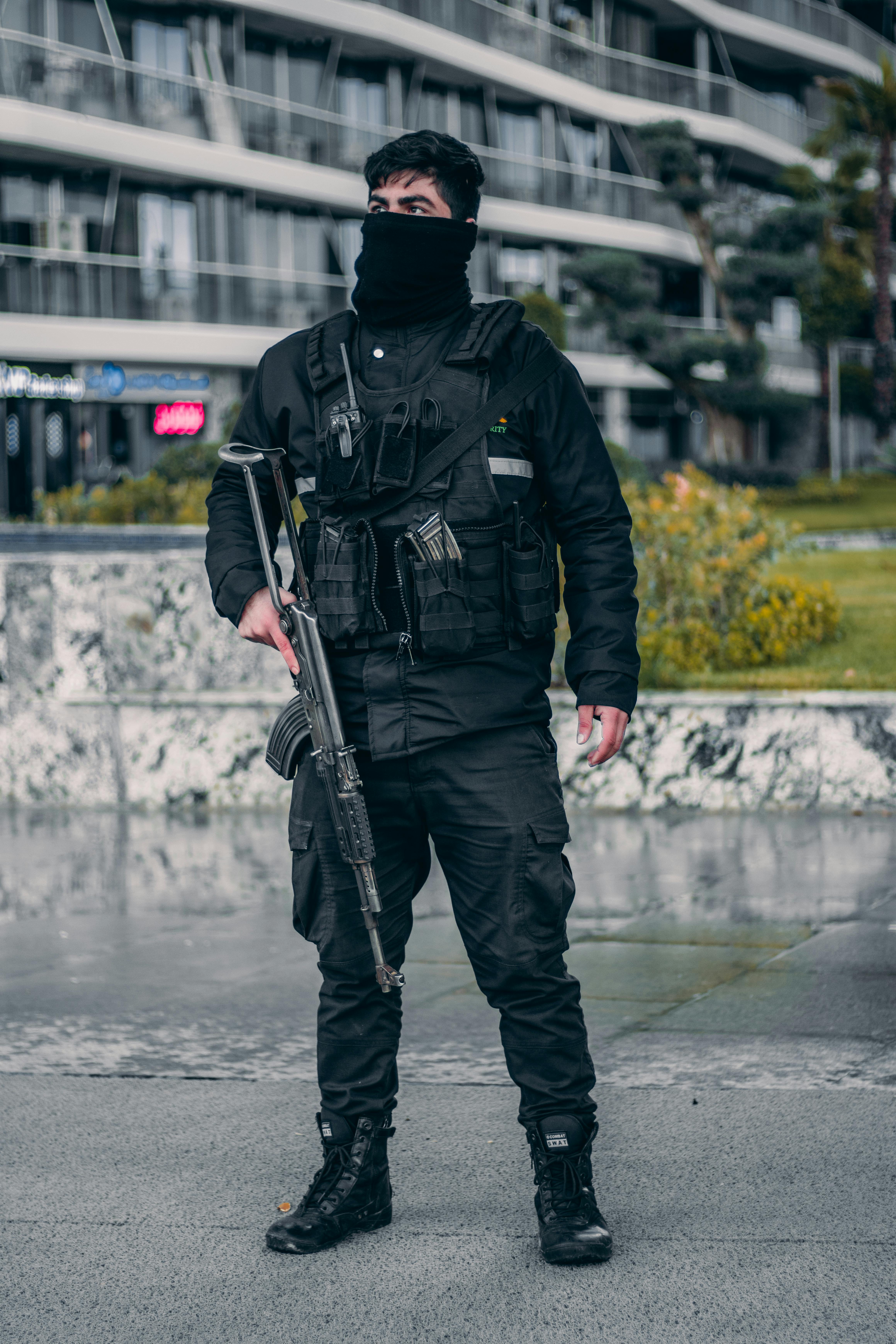 Man Armed with Rifle Standing on Sidewalk · Free Stock Photo