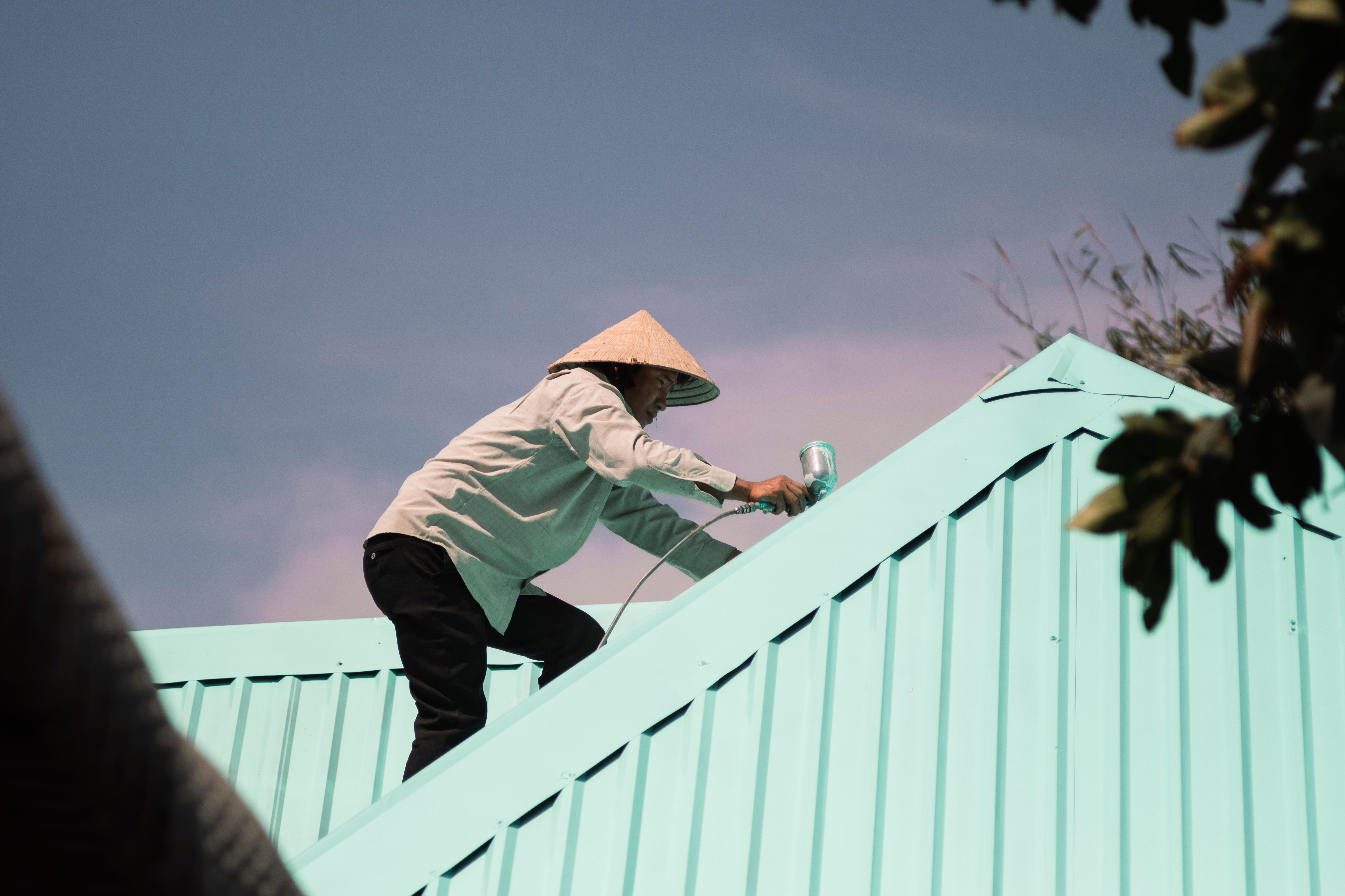 Man in Conical Hat Working on Roof · Free Stock Photo