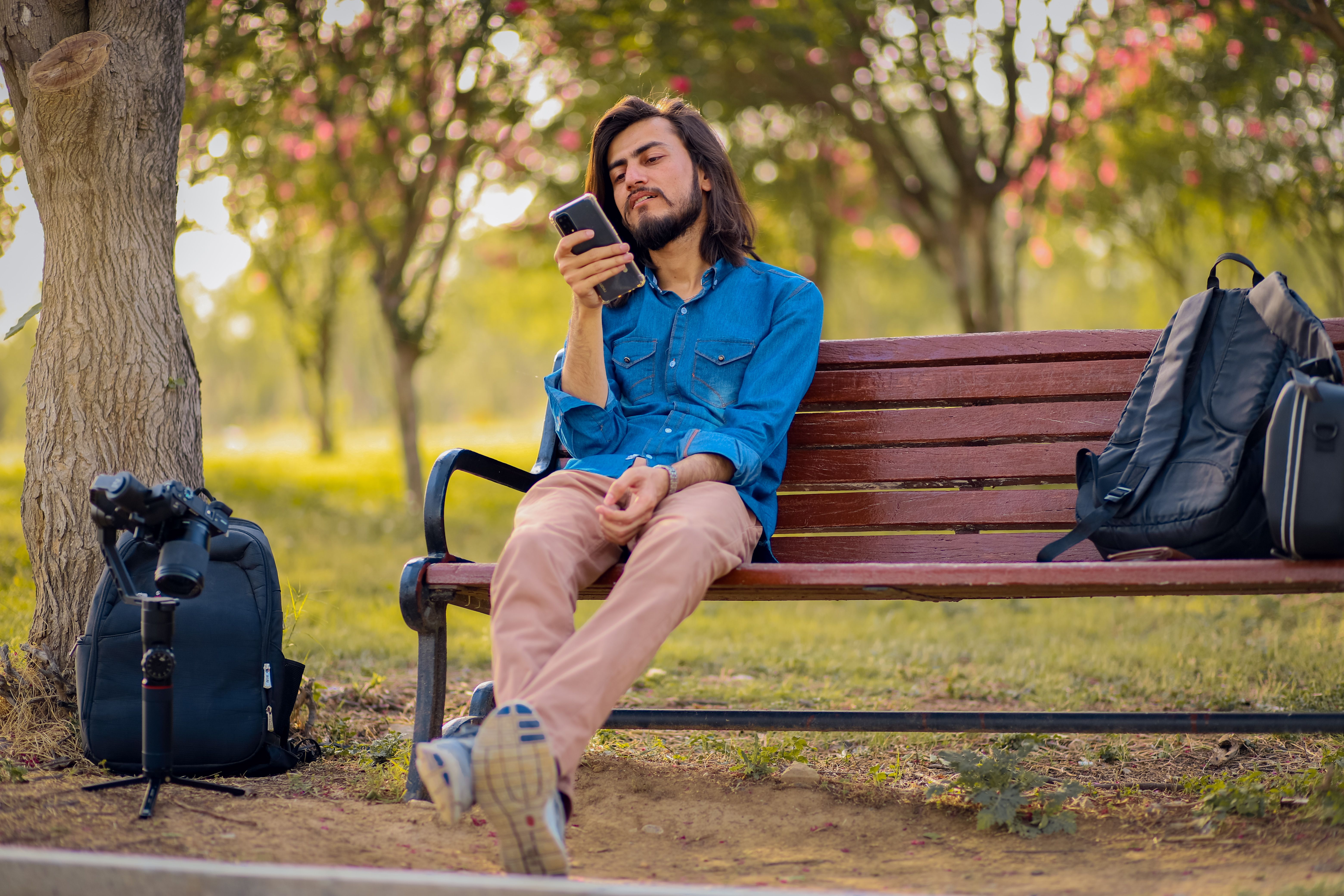 A Man Sitting on a Bench while Using His Phone · Free Stock Photo
