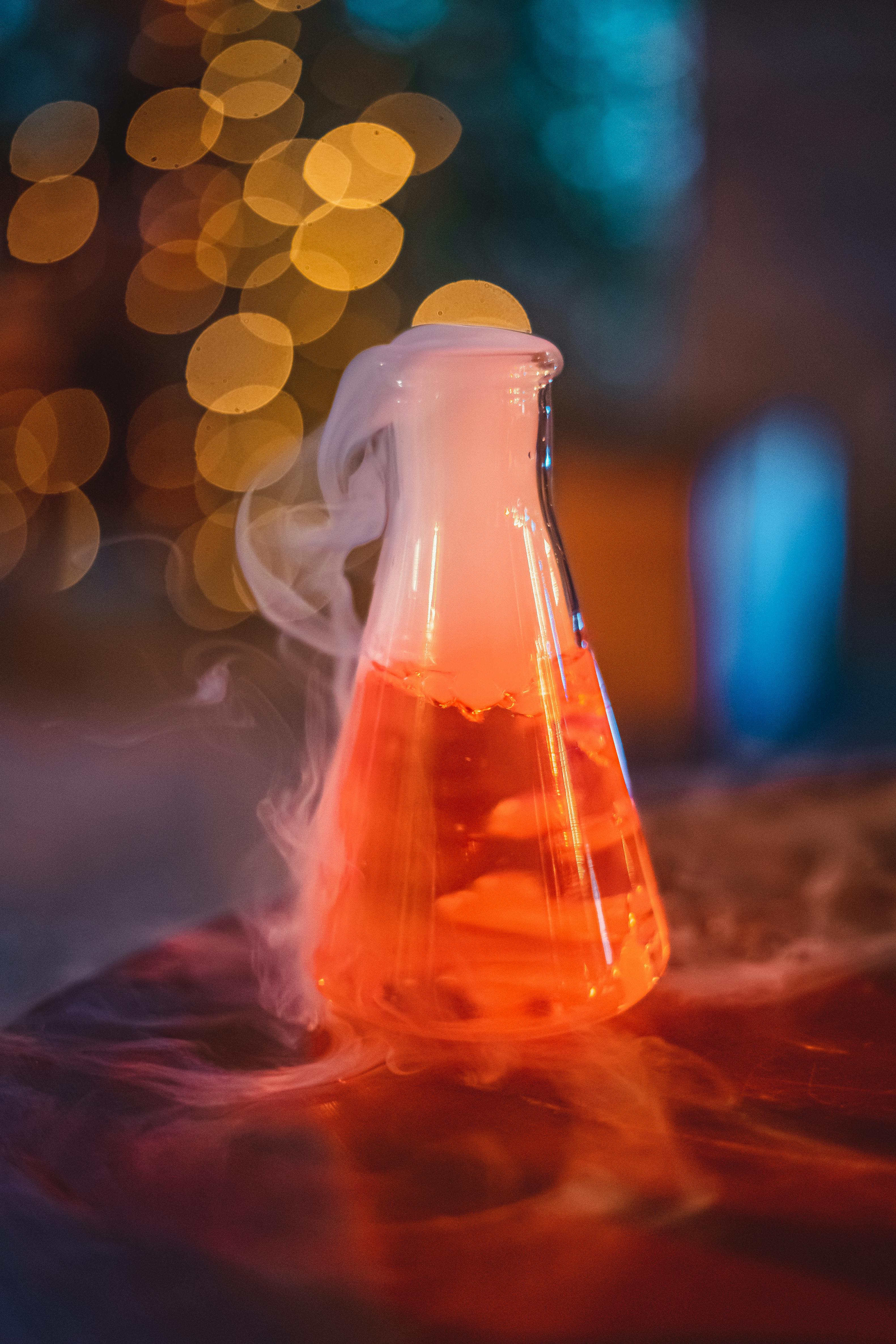 A Smoke Coming Out of a Beaker with Orange Liquid · Free Stock Photo