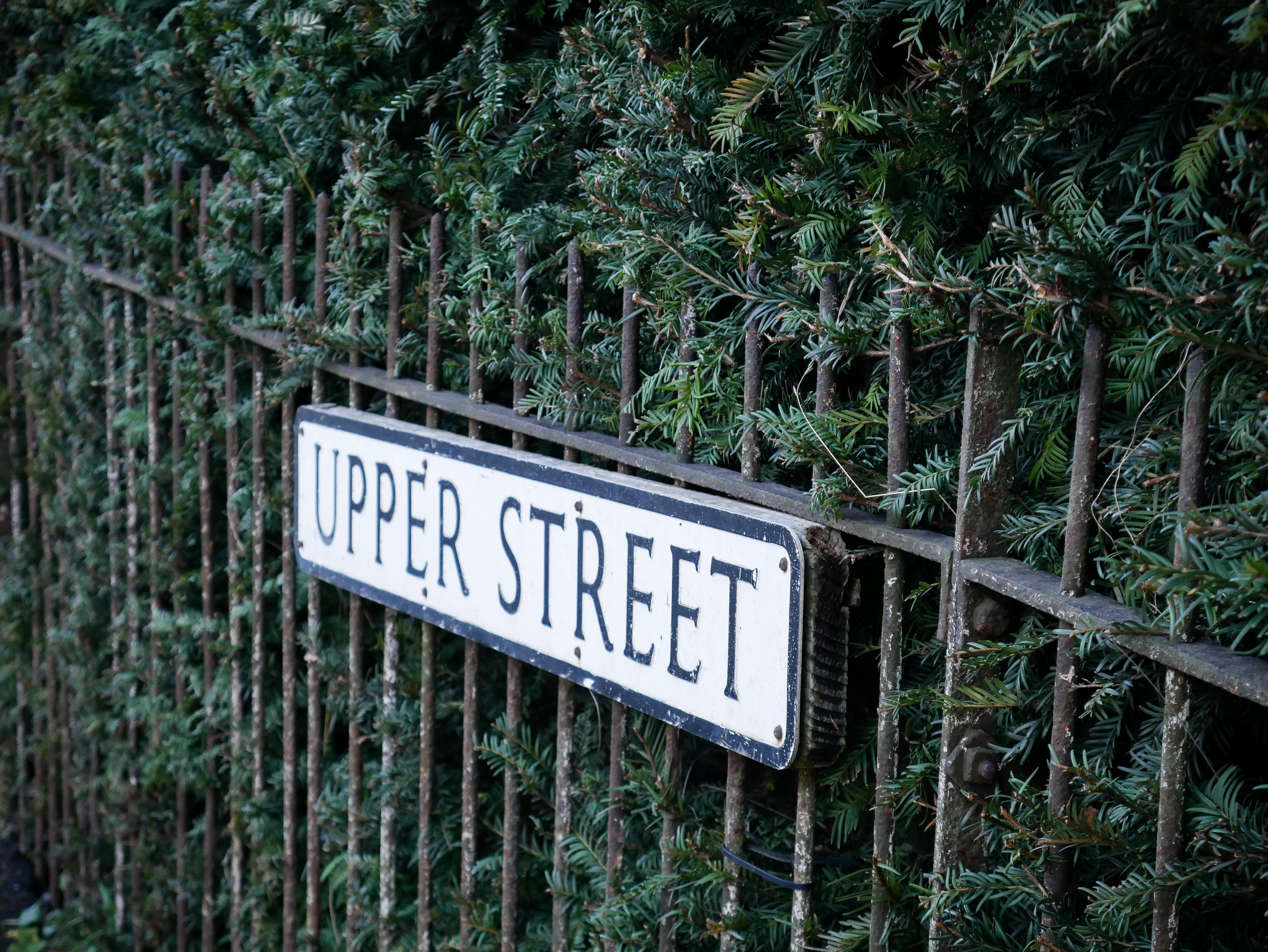 Close-up of a Sign with Street Name on a Fence · Free Stock Photo