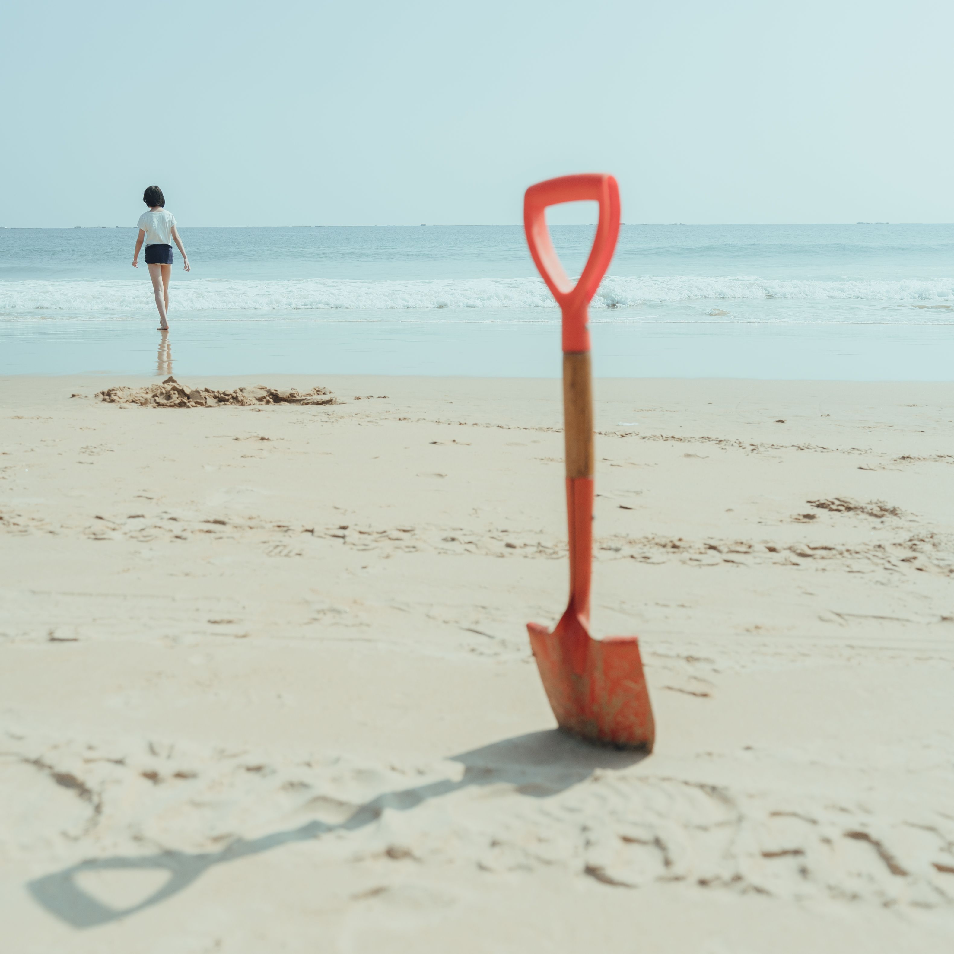 Yellow Shovel Half Buried on Sand Near the Ocean · Free Stock Photo