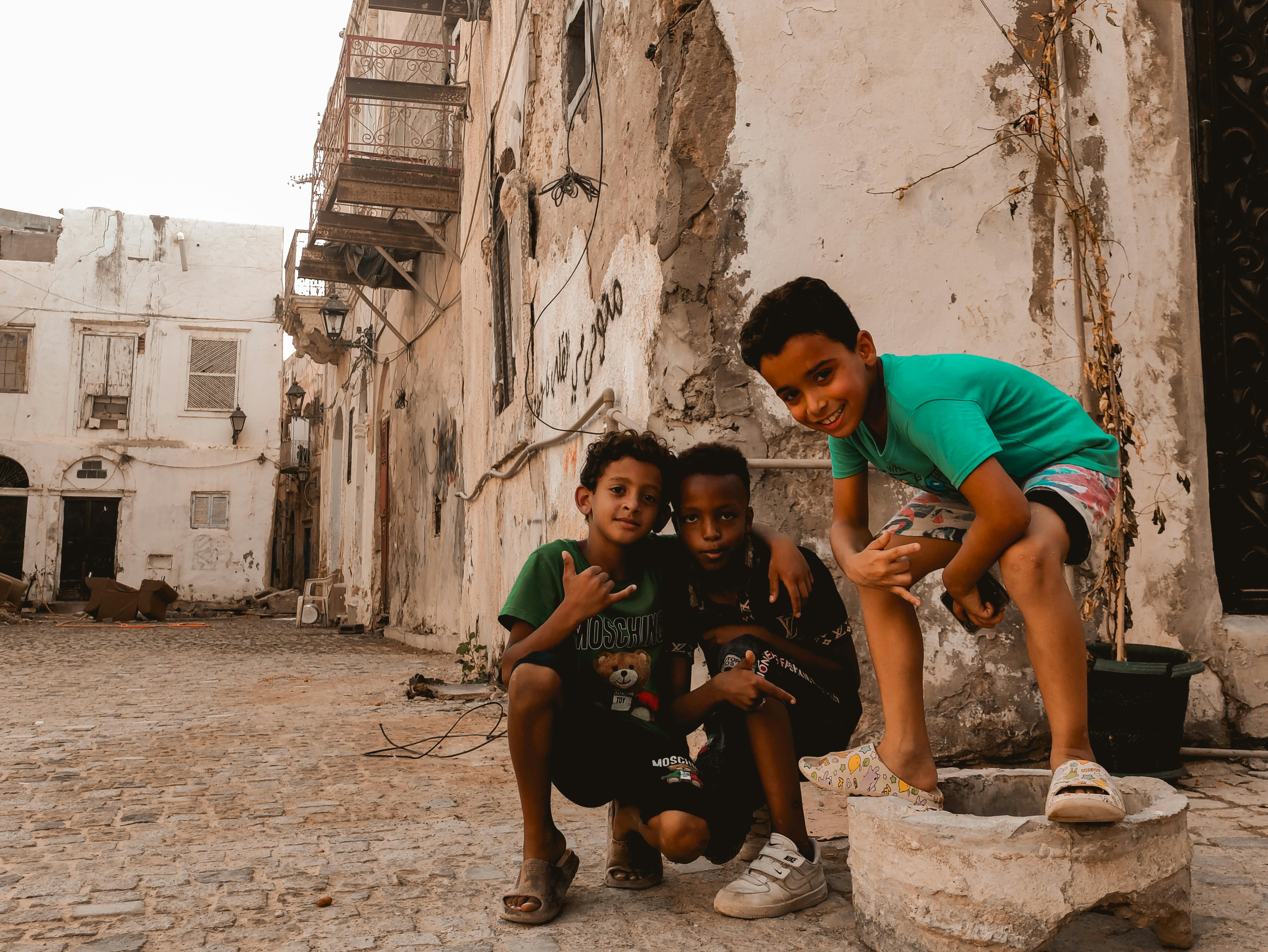 A Group of Boys Crouching in front of Damaged Buildings · Free Stock Photo