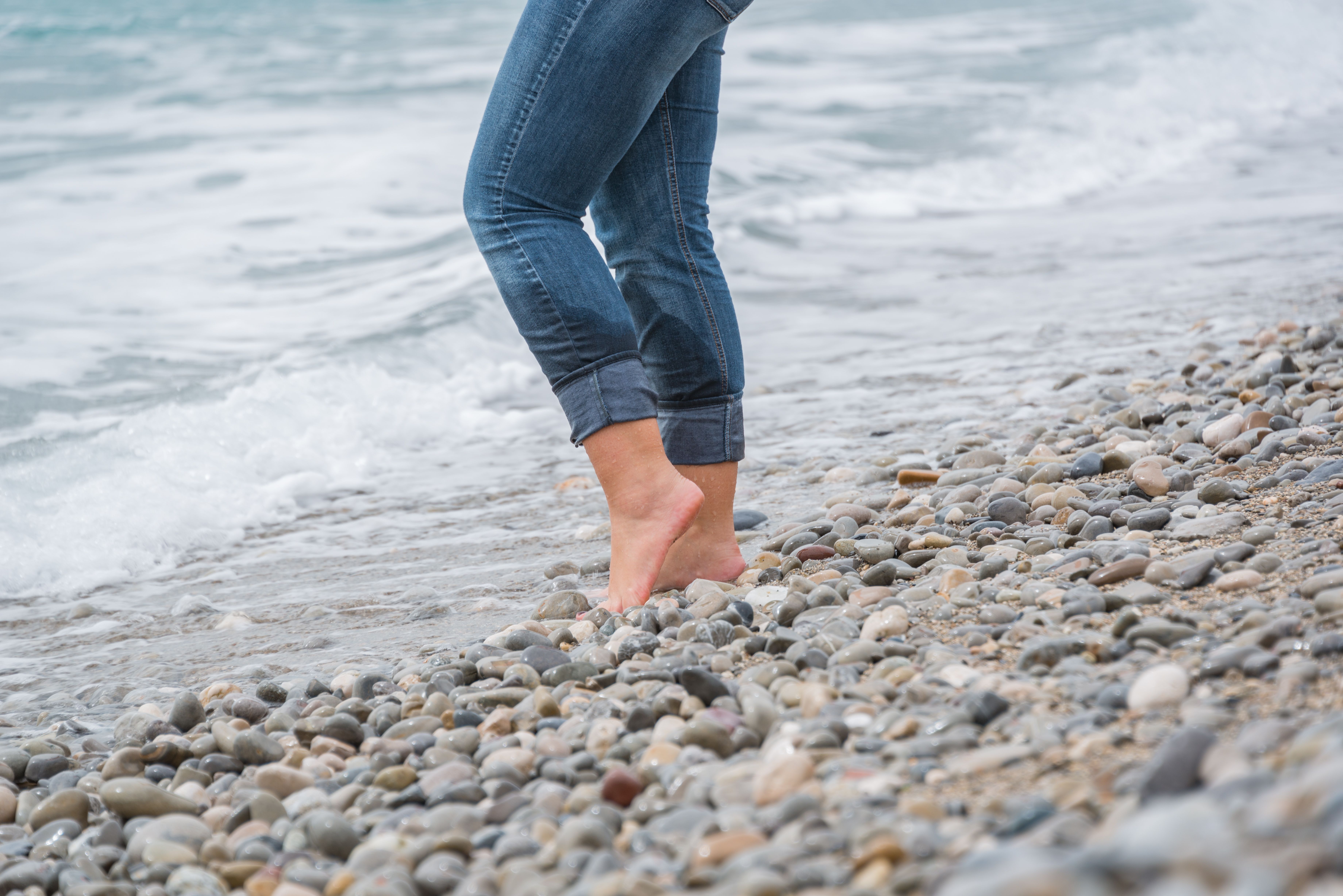 Legs in Jeans on Pebbles on Shore · Free Stock Photo