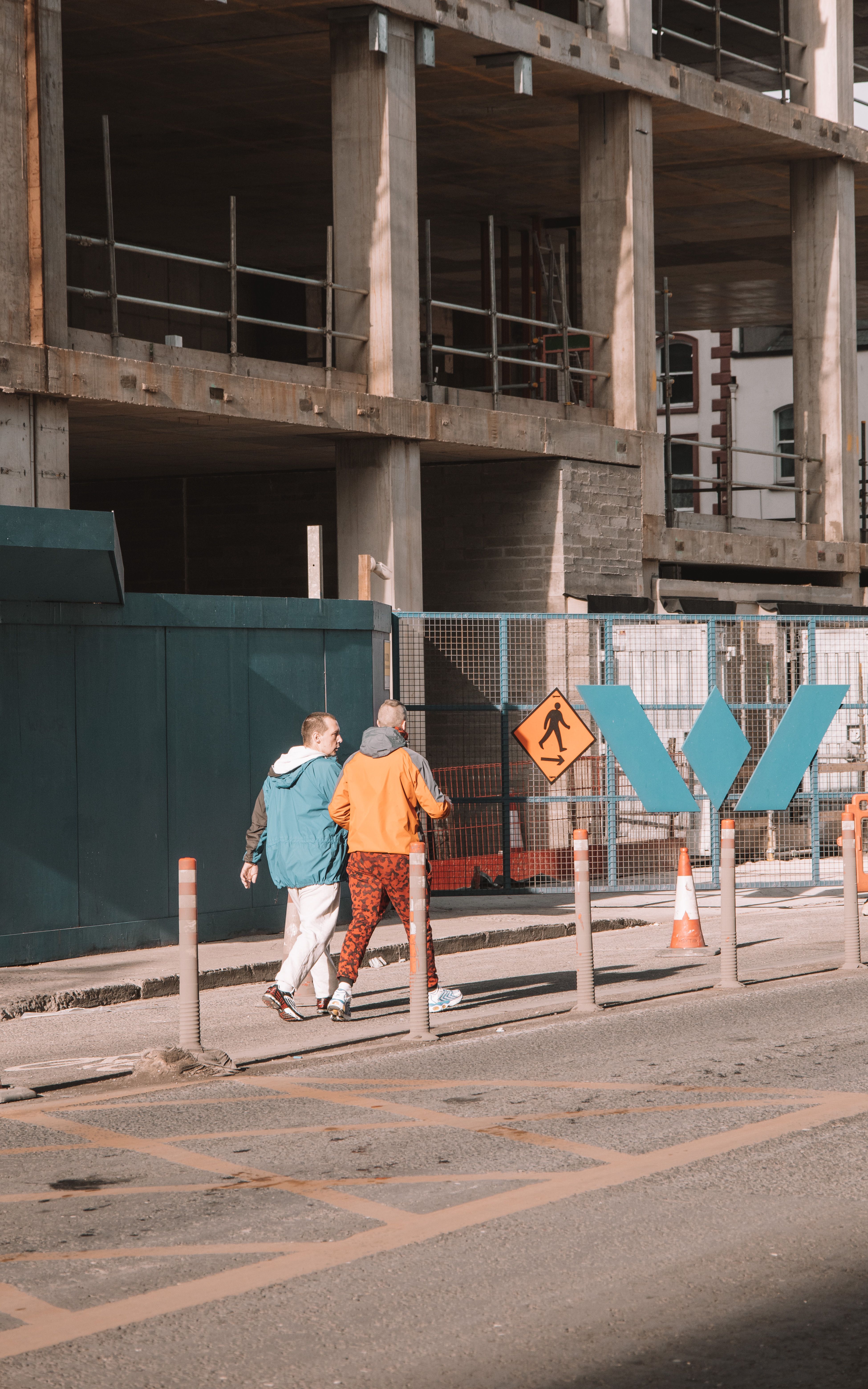 Men Walking on Street past Building under Constru · Free Stock Photo