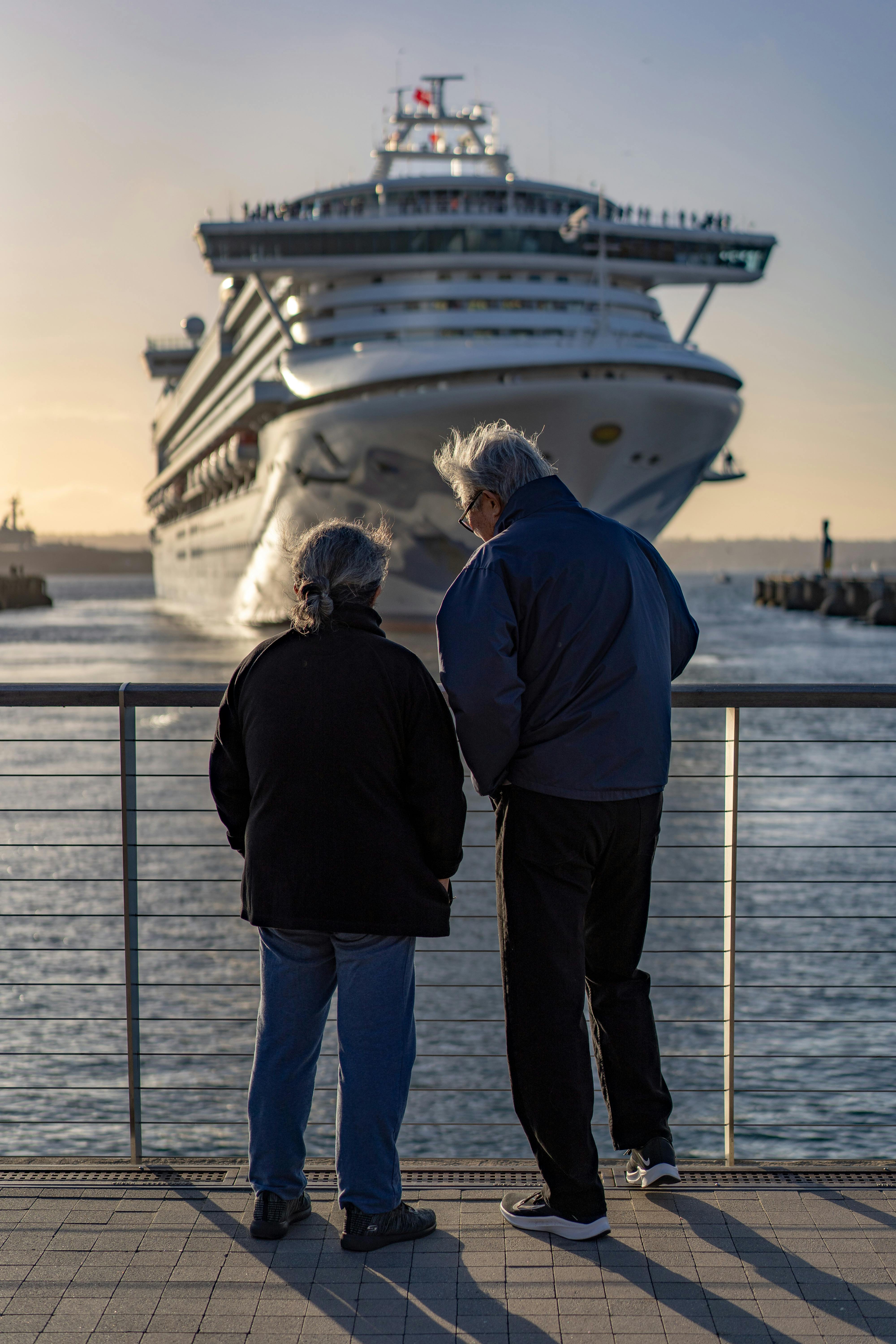 Elderly Couple in Jackets Standing by a Railing Watching a Ship · Free ...