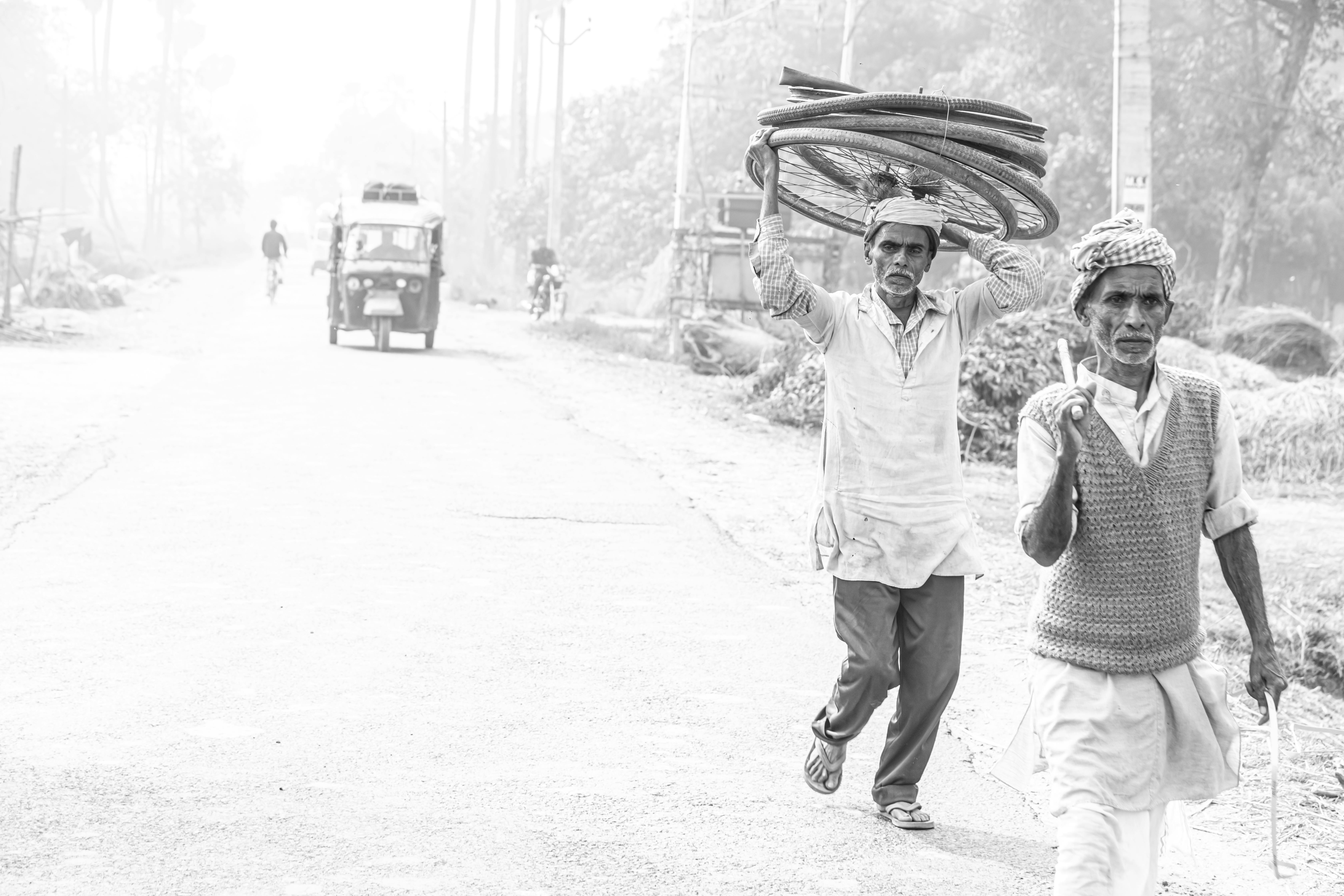 Photo of Men Walking in a Village and an Auto Rickshaw Driving behind ...