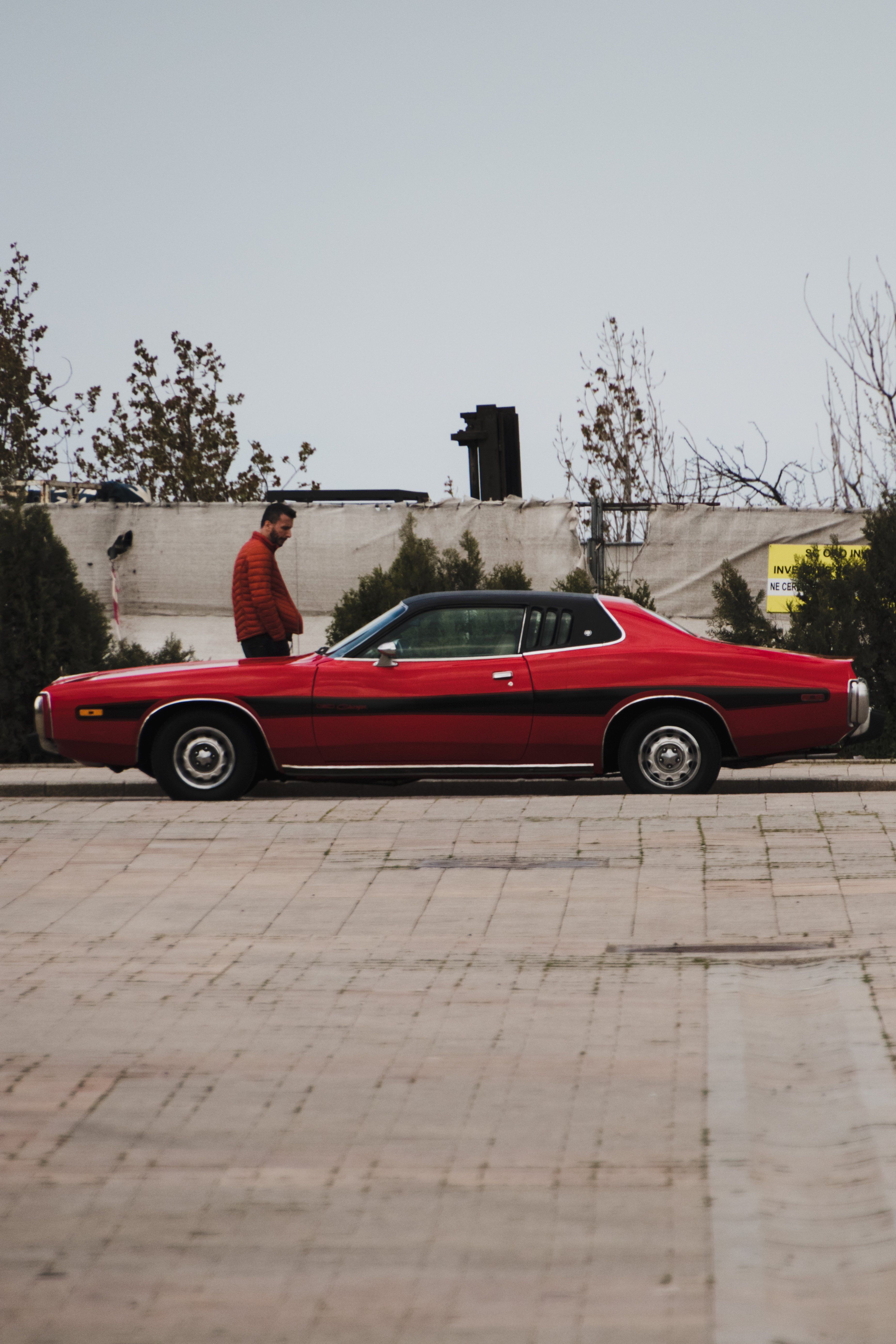 Man Standing next to a Red, Vintage Dodge Charger · Free Stock Photo