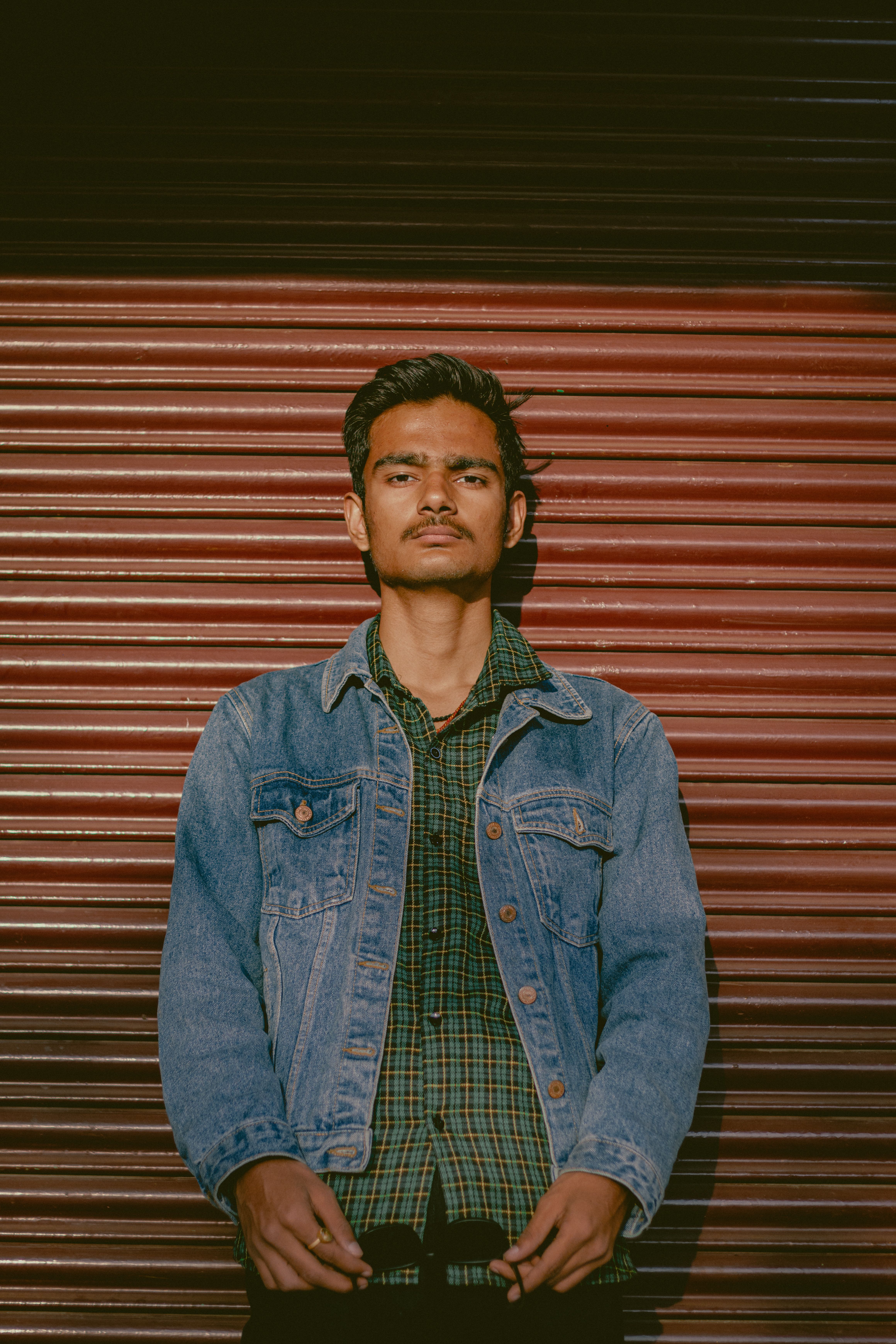 Standing Man in Denim Jacket Holding Shades · Free Stock Photo