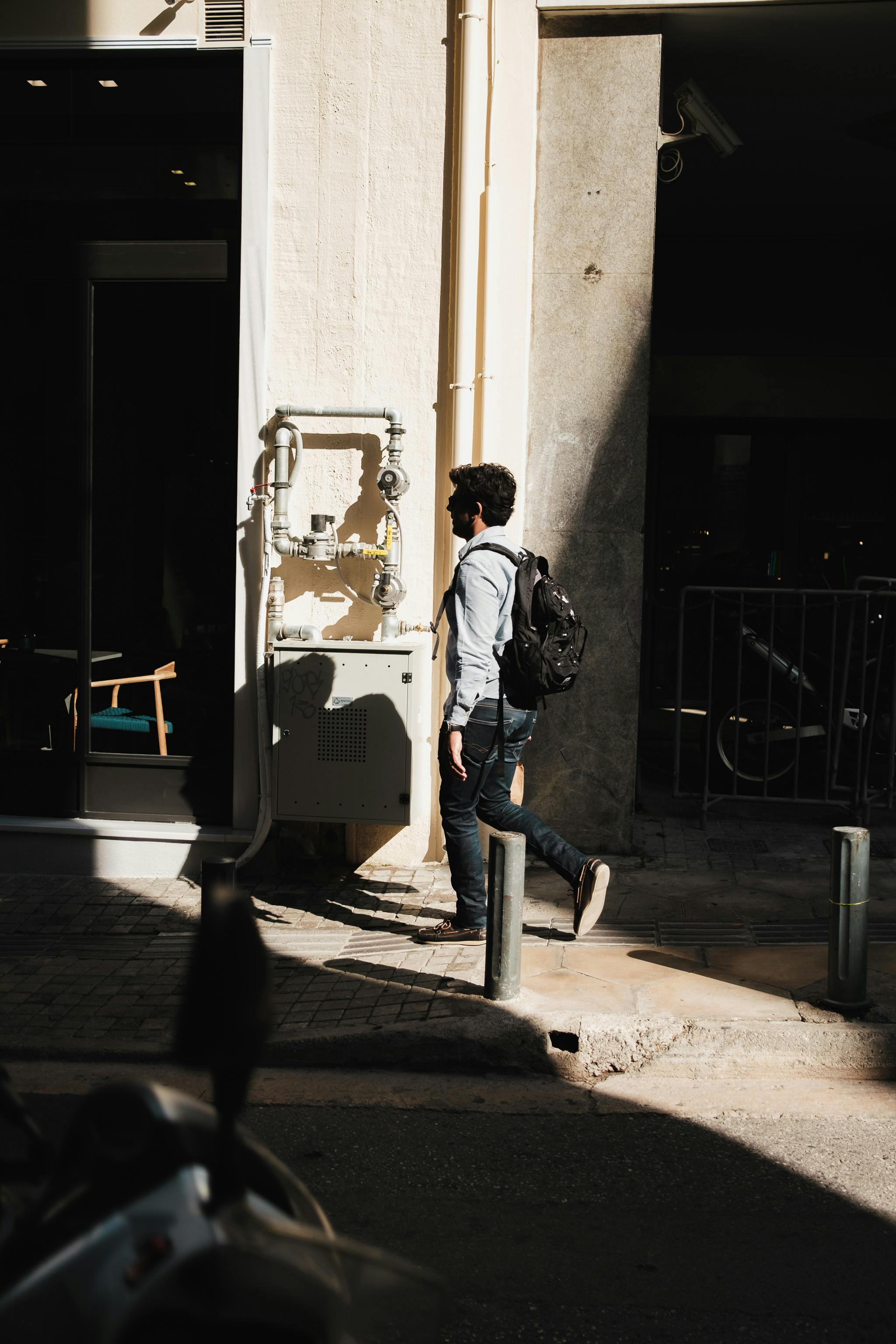 Passerby with a Backpack Walking on the Sidewalk · Free Stock Photo