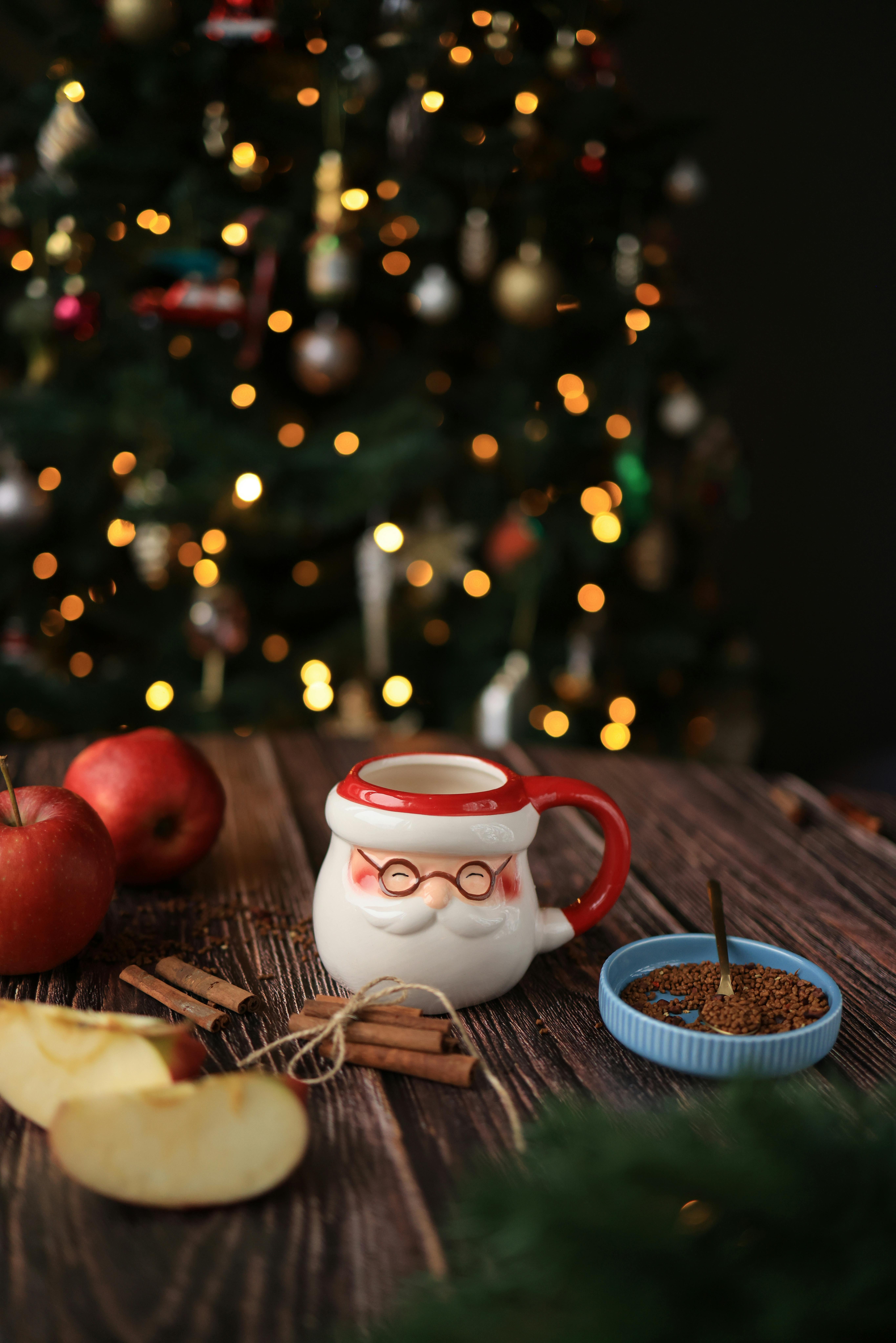 Table with a Mug in form of Santa Claus Head, Cinnamons, Apples and ...