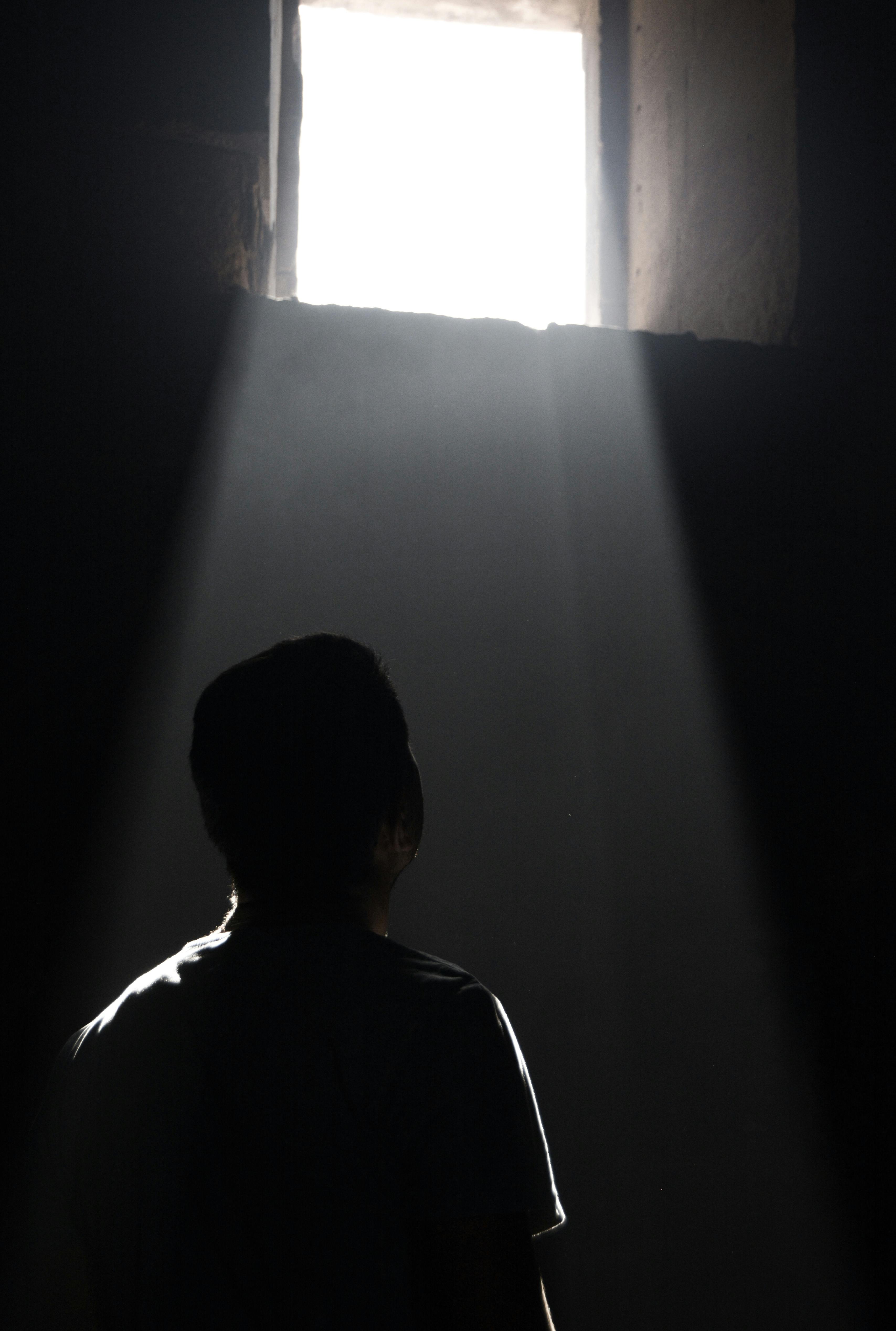 Man in a Cell Looking at Light Coming from a Window · Free Stock Photo