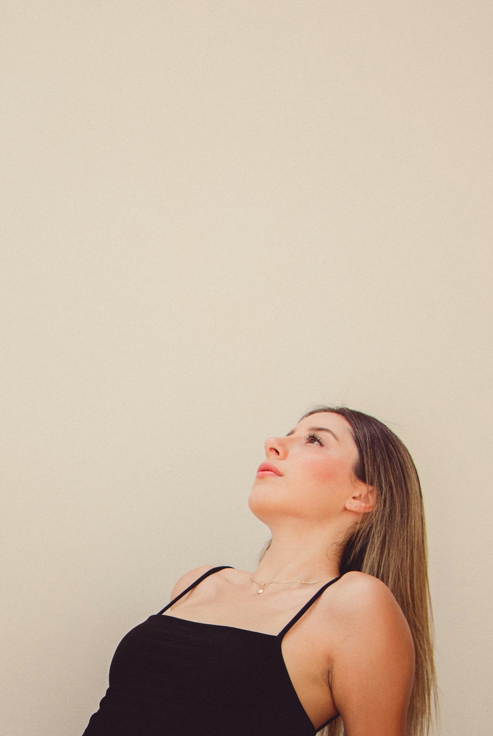 Young Woman Leaning Backwards on a Plain Background · Free Stock Photo