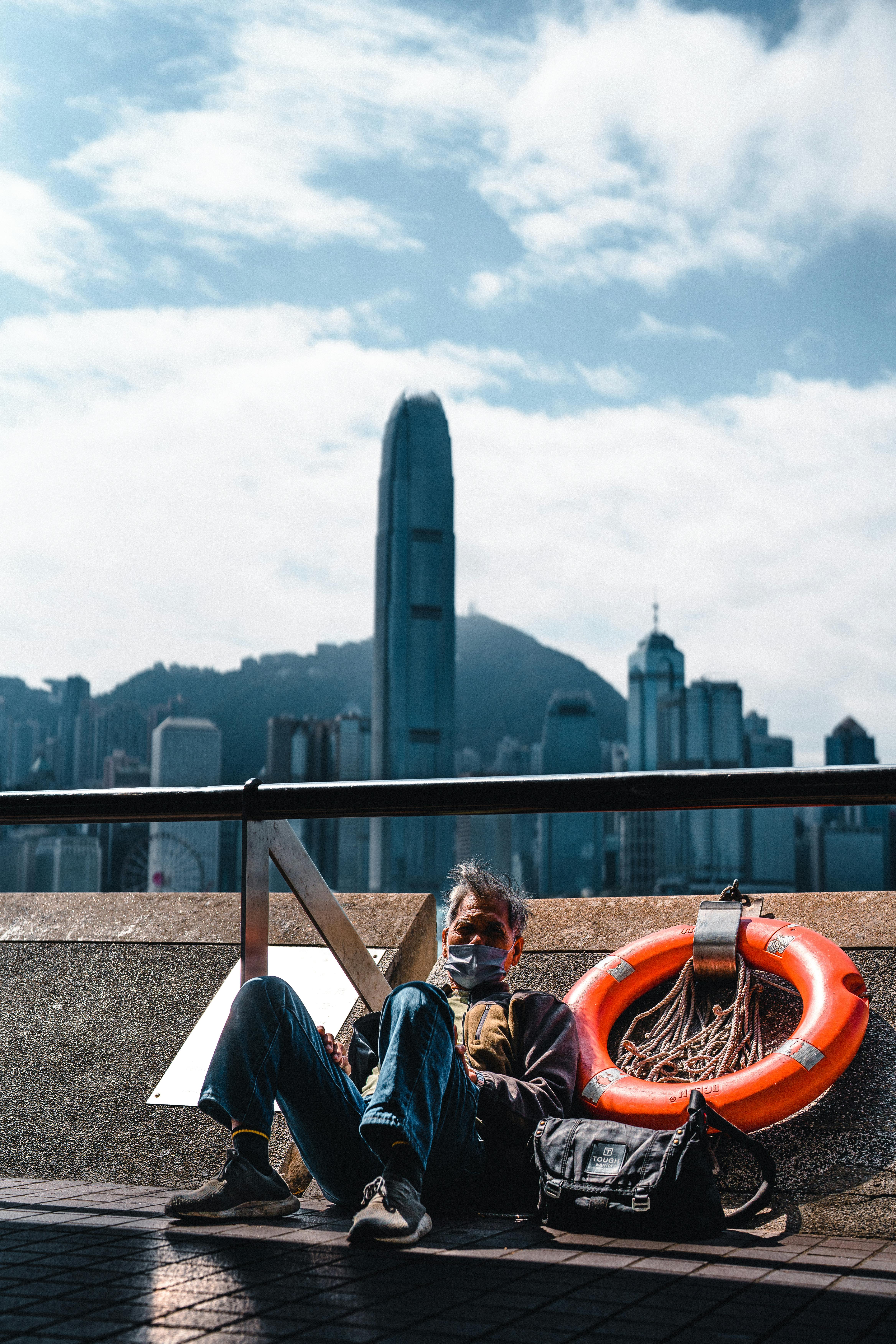 Man Sitting Next to a Lifebuoy on the Hong Kong Promenade · Free Stock ...