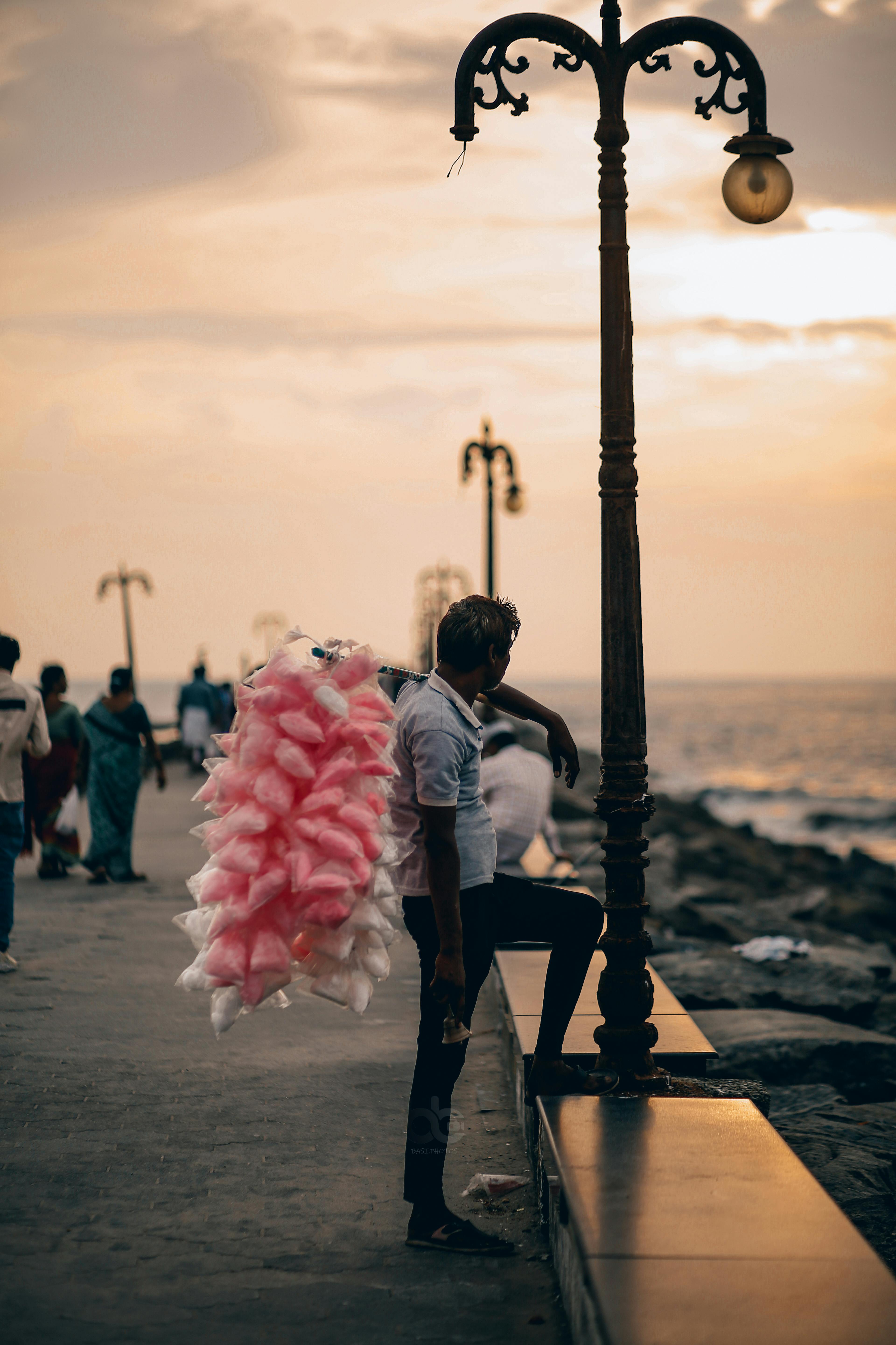 Man Posing with Cotton Candy on Promenade at Sunset · Free Stock Photo