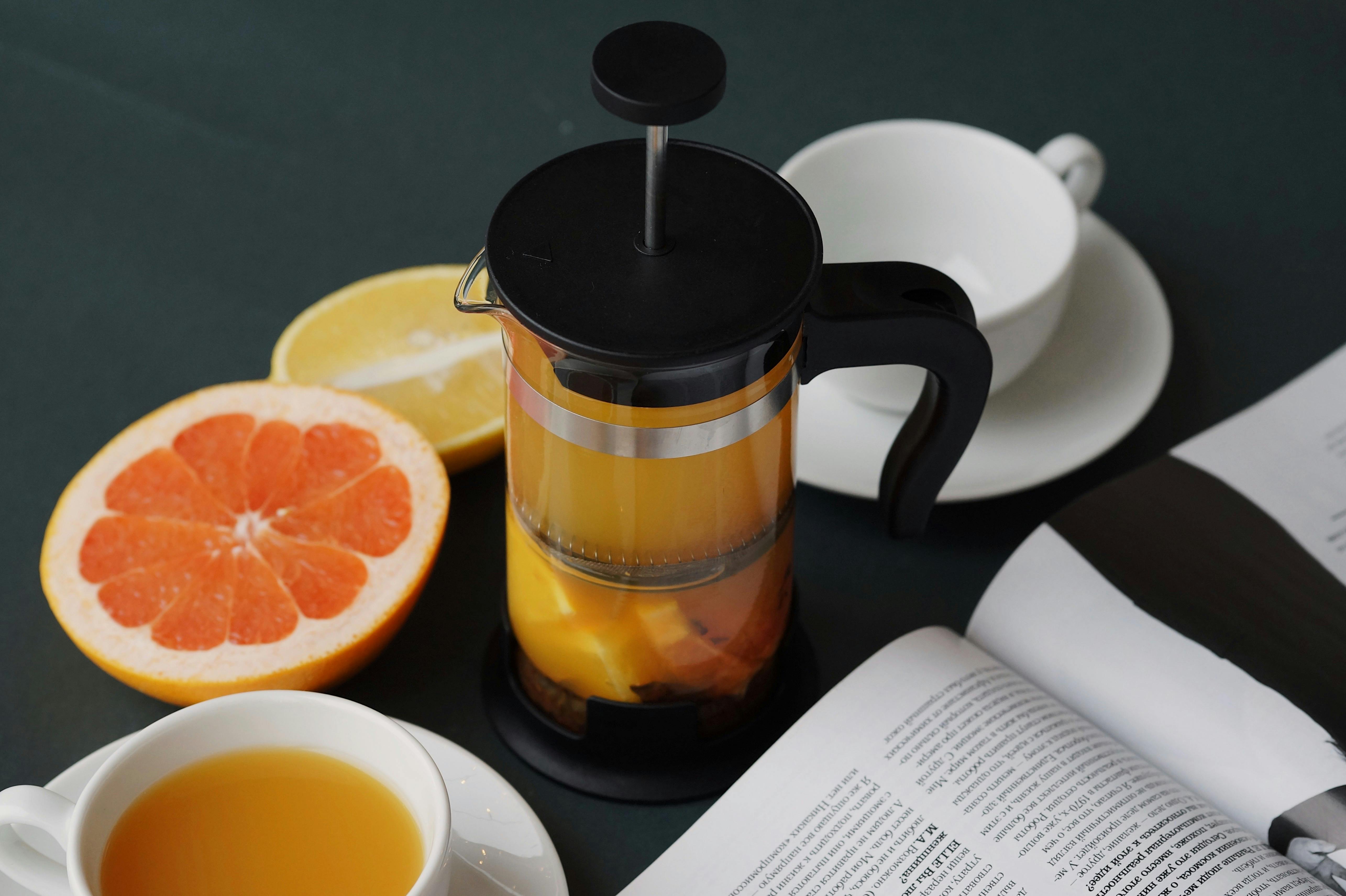 Fruit Squeezer and Cups of Juice on a Table · Free Stock Photo