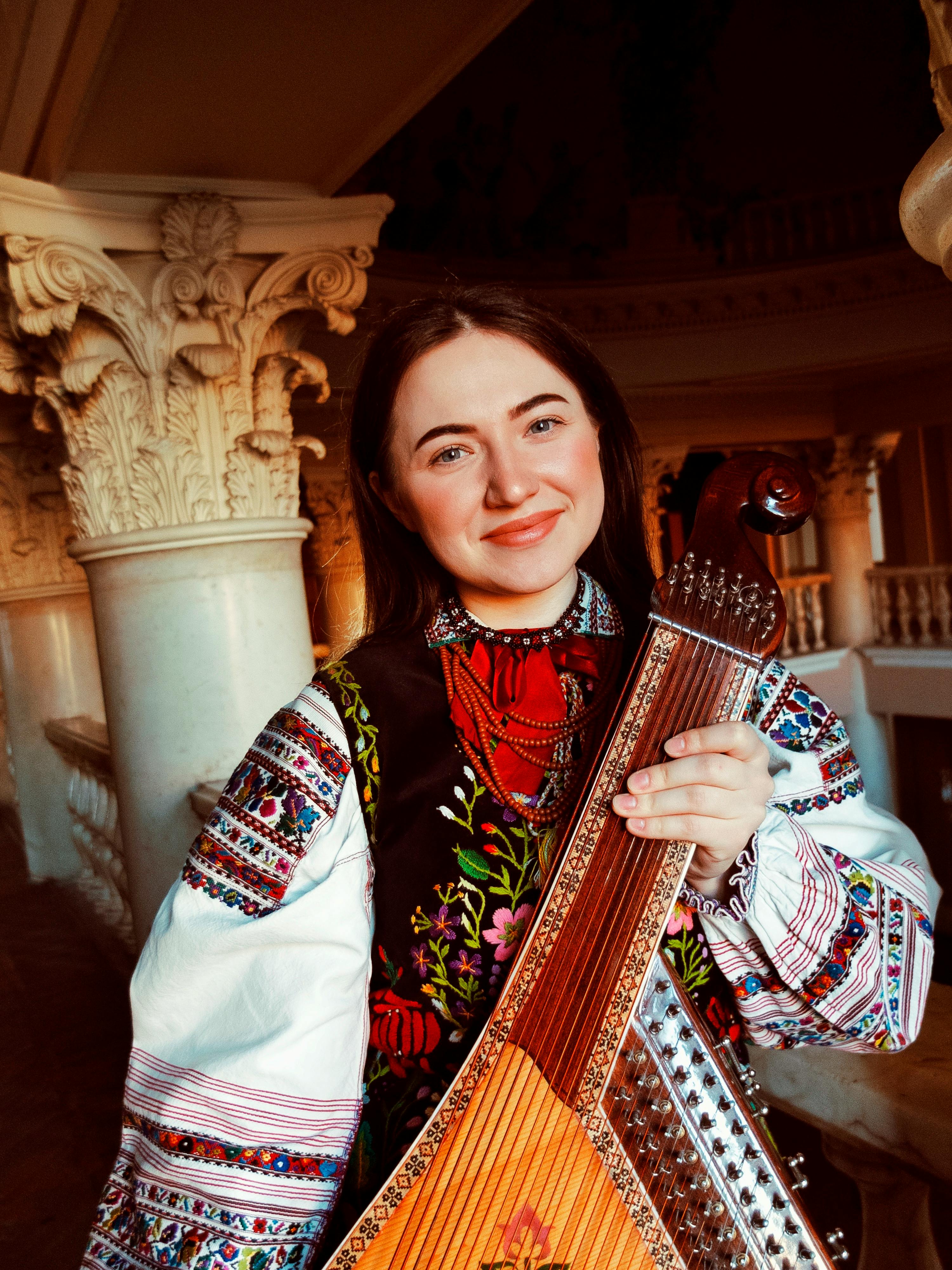 A Young Woman Holding a Traditional Instrument · Free Stock Photo