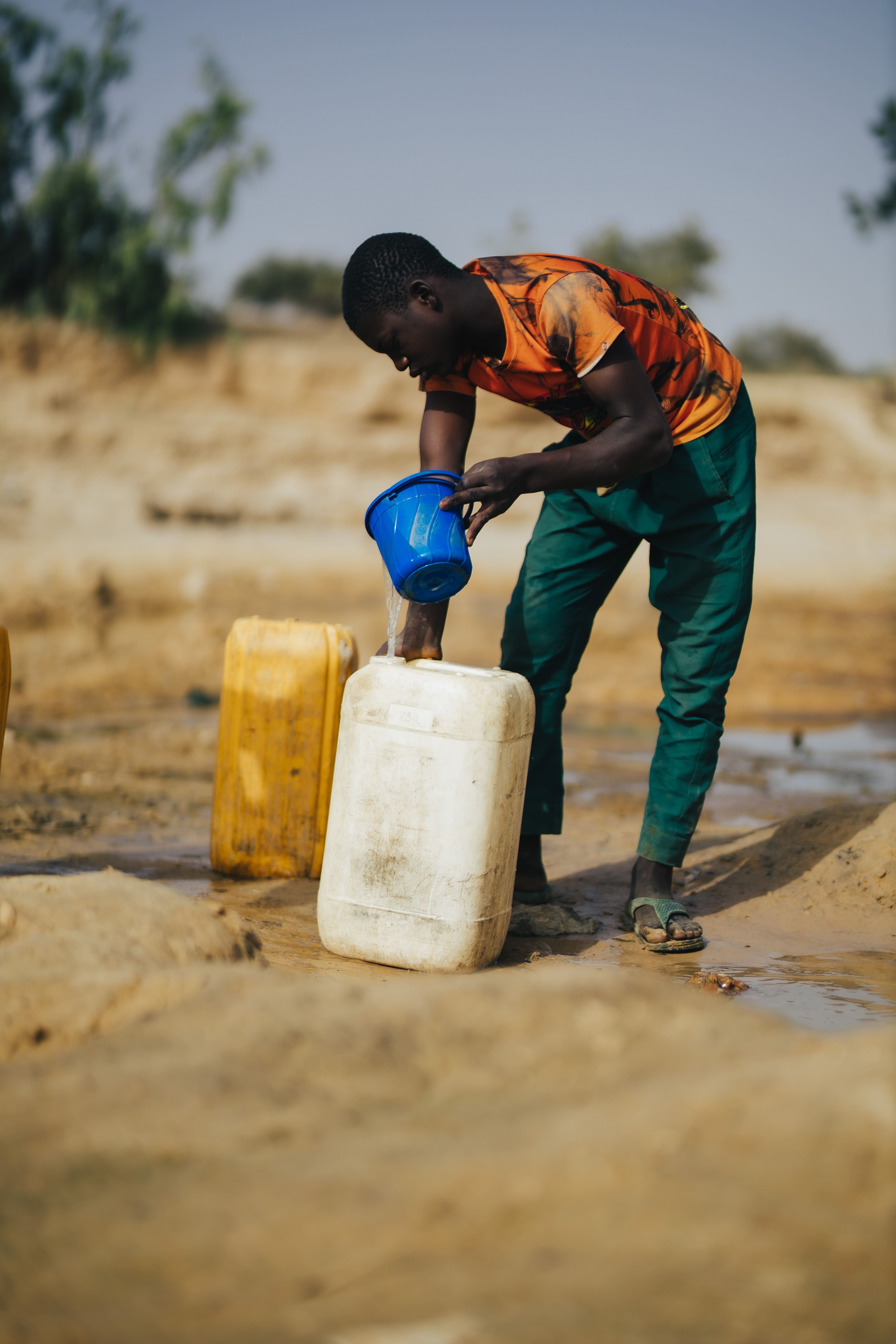 Man Filling Containers with Water · Free Stock Photo