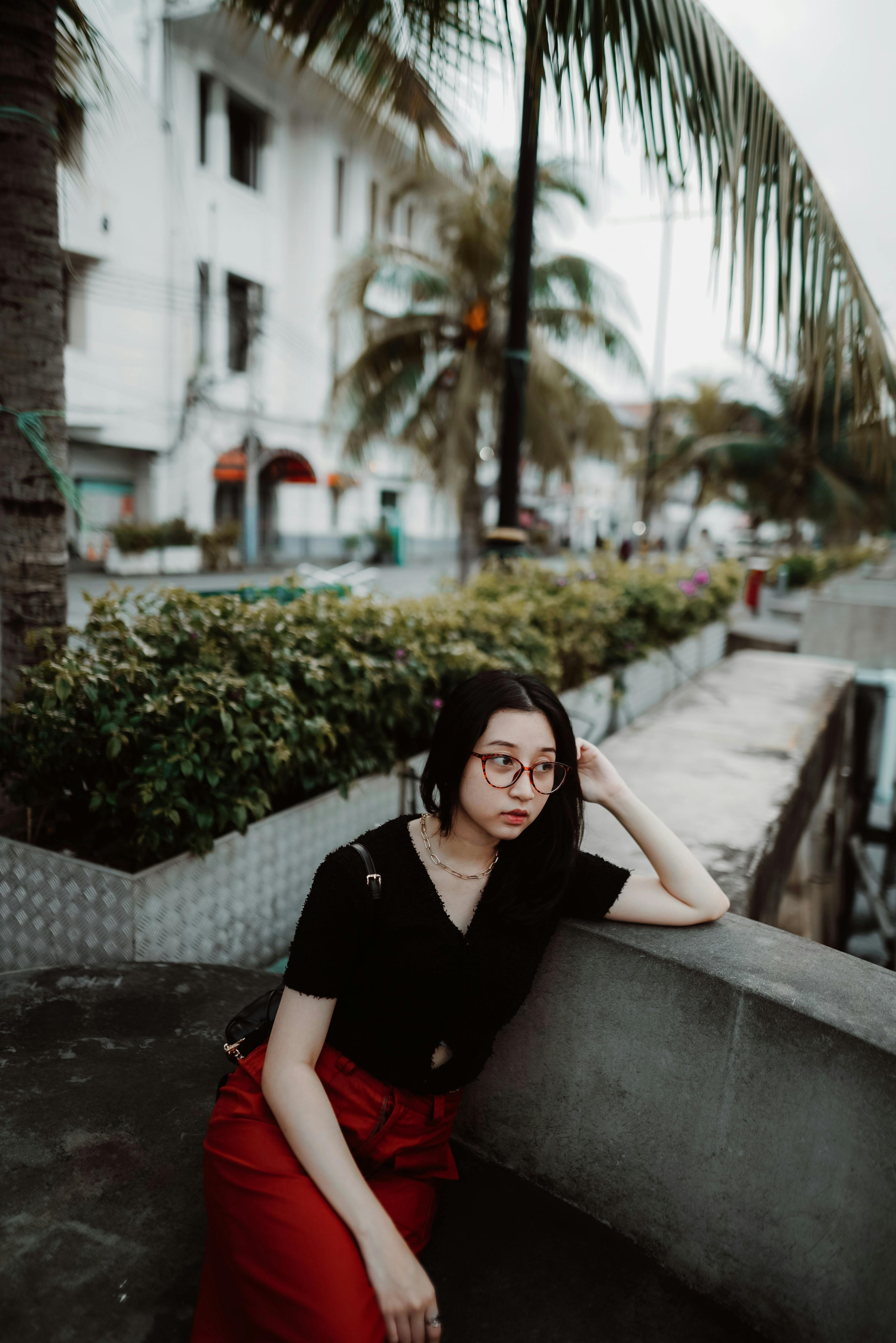 Young Brunette Sitting under a Palm Tree in City · Free Stock Photo