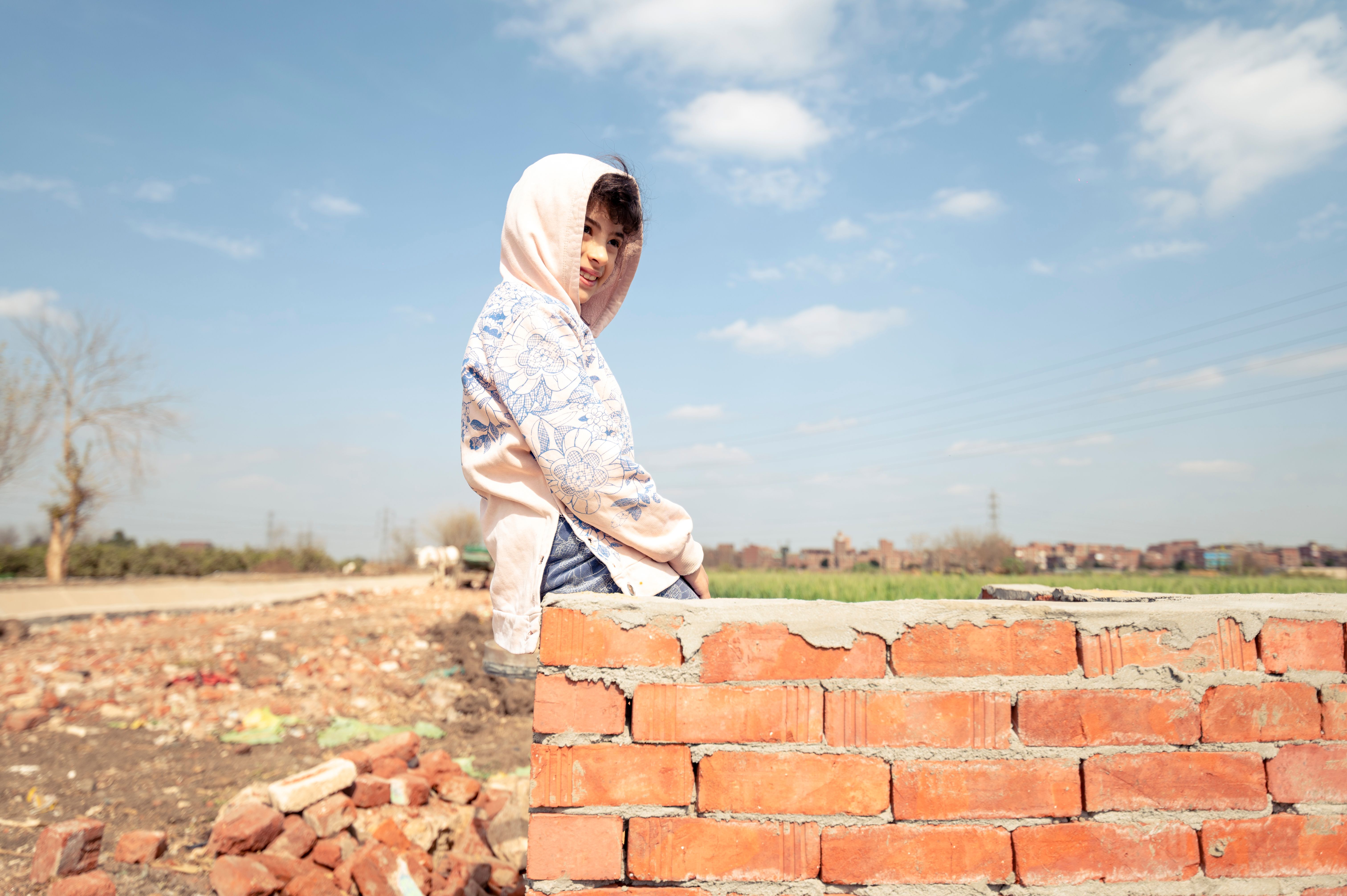 Teenager Sitting on Bricks Wall · Free Stock Photo