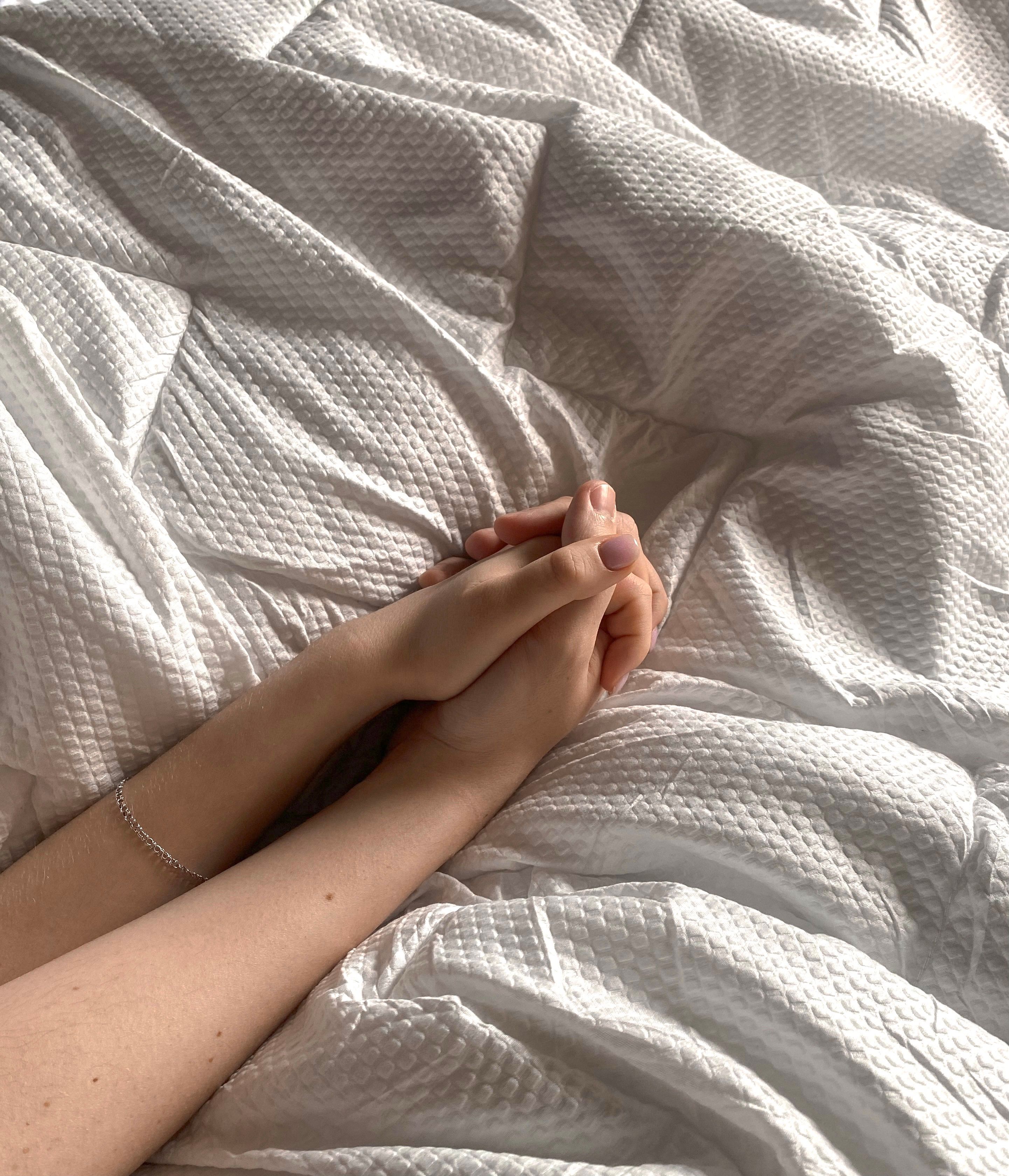 Crossed Hand on Bedding · Free Stock Photo