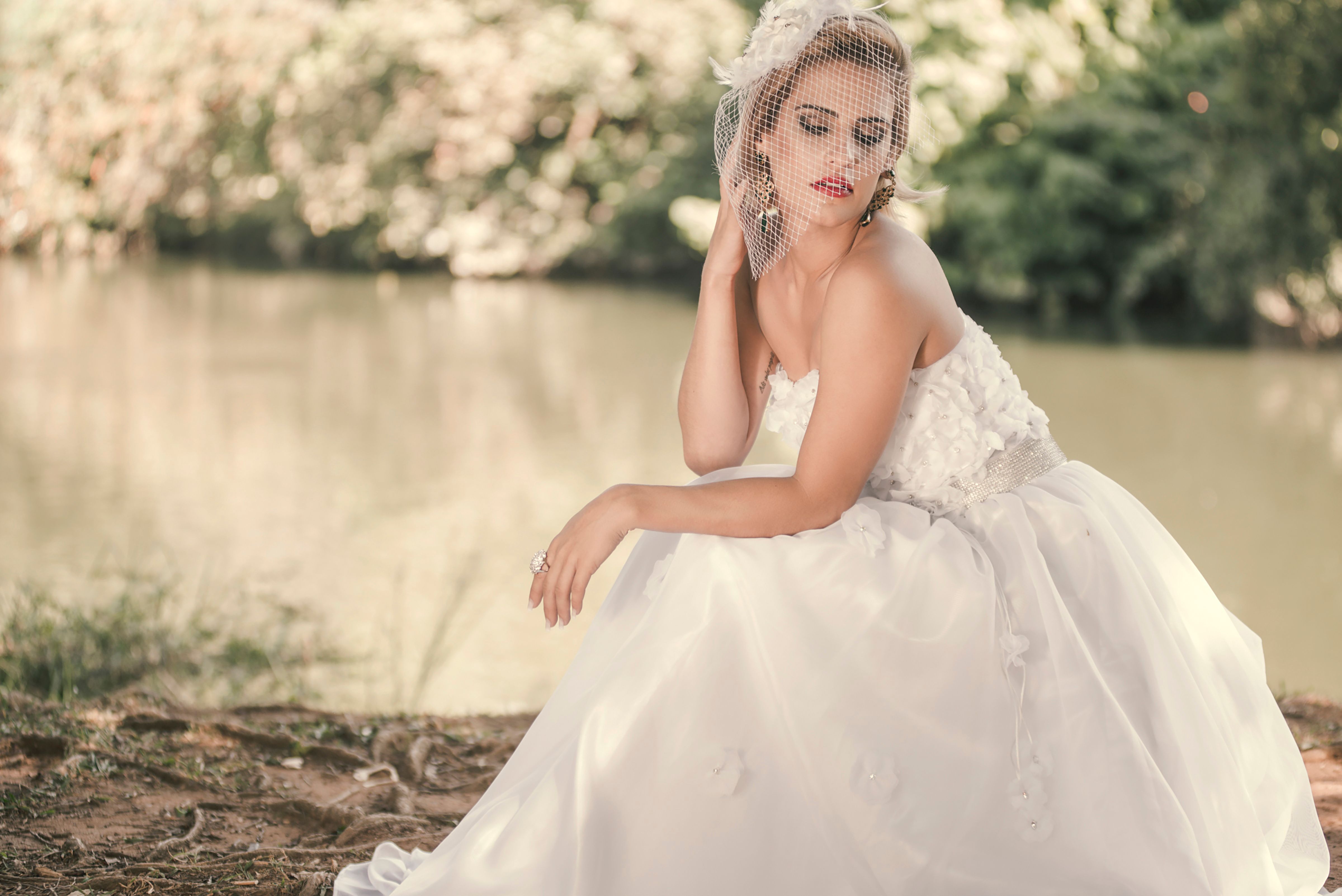Bride Sitting in Wedding Dress near River · Free Stock Photo