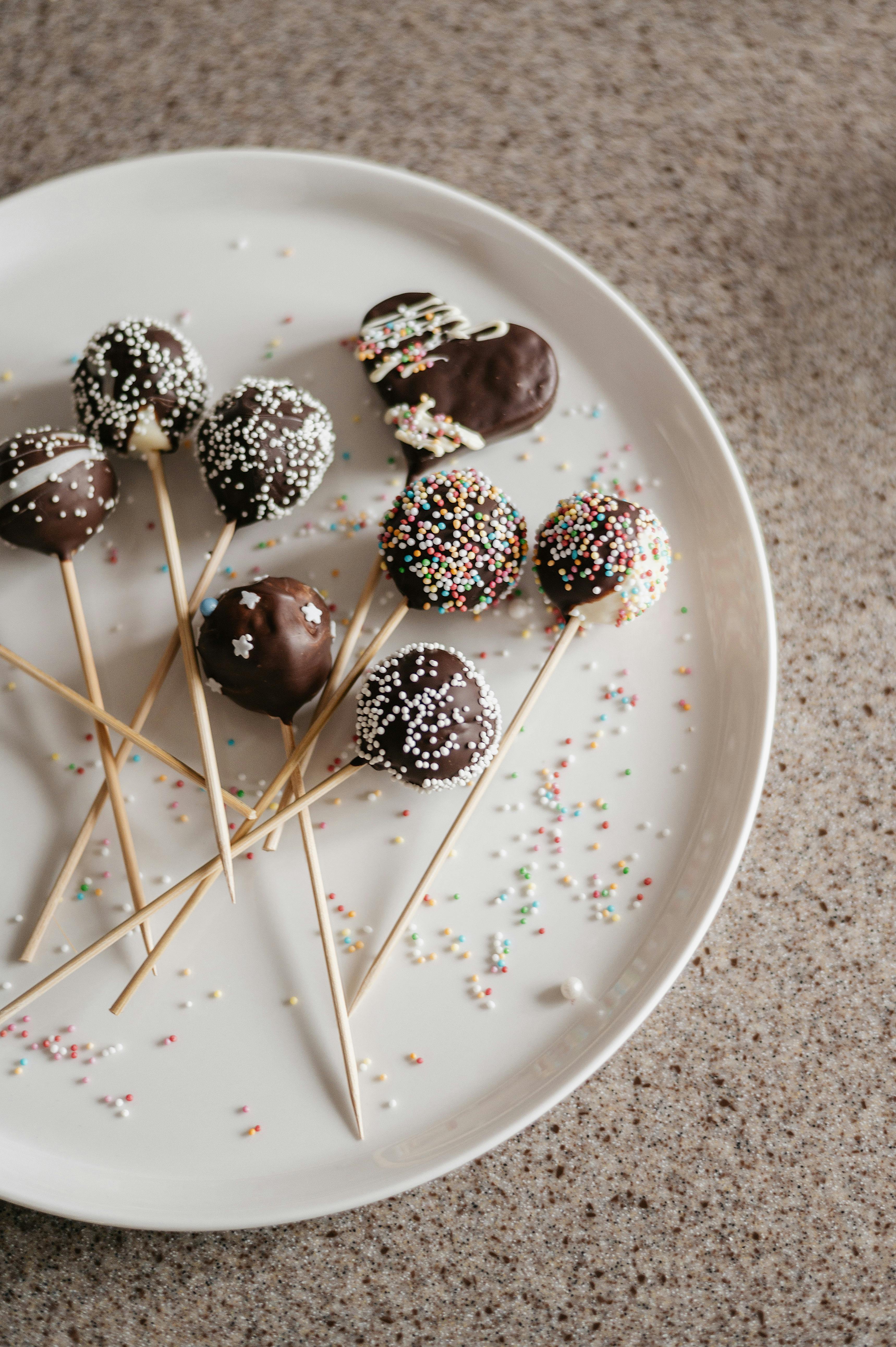 A plate with chocolate covered cake pops on sticks · Free Stock Photo