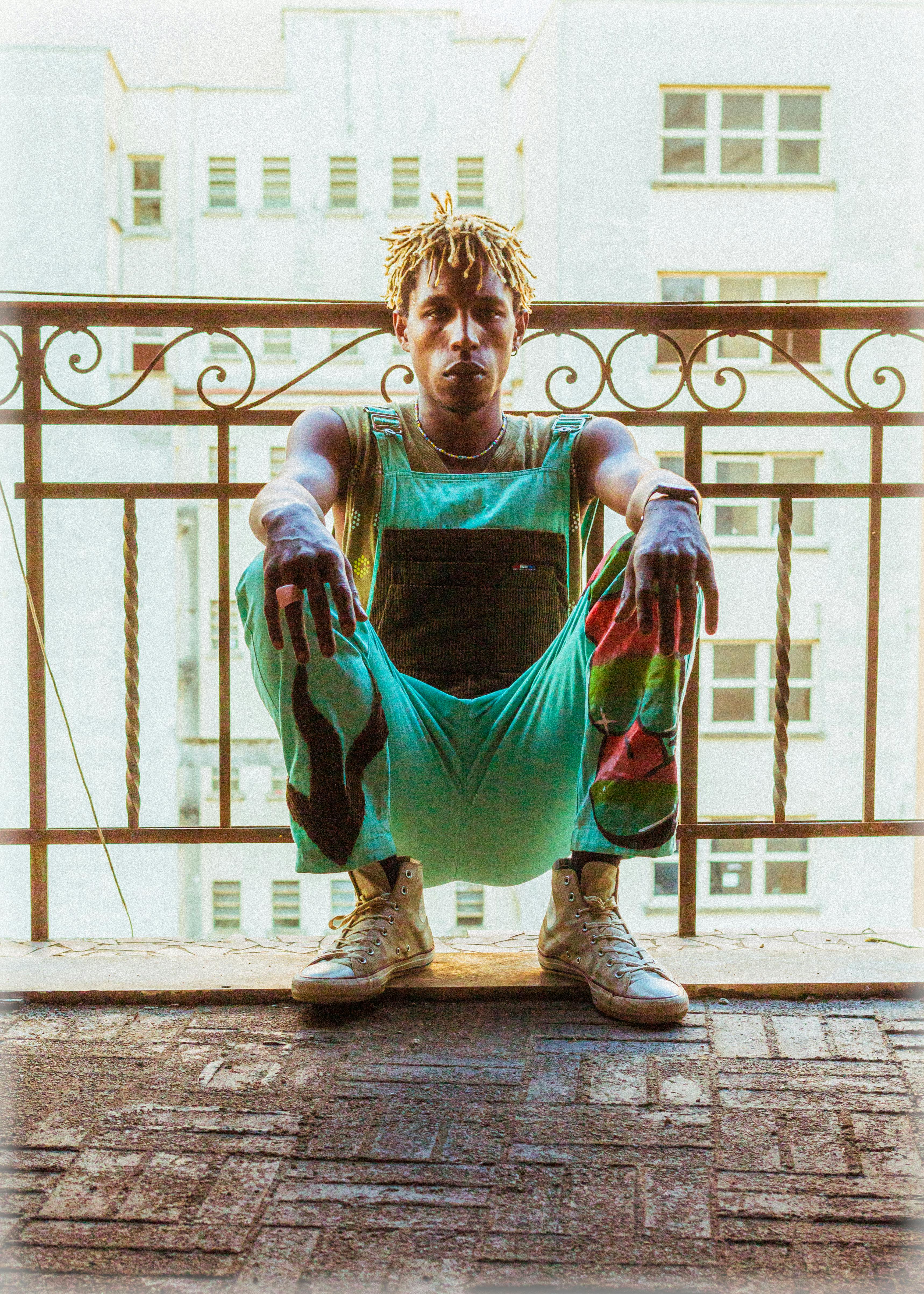 Photo of a Cool Young Man Crouching on a Balcony · Free Stock Photo