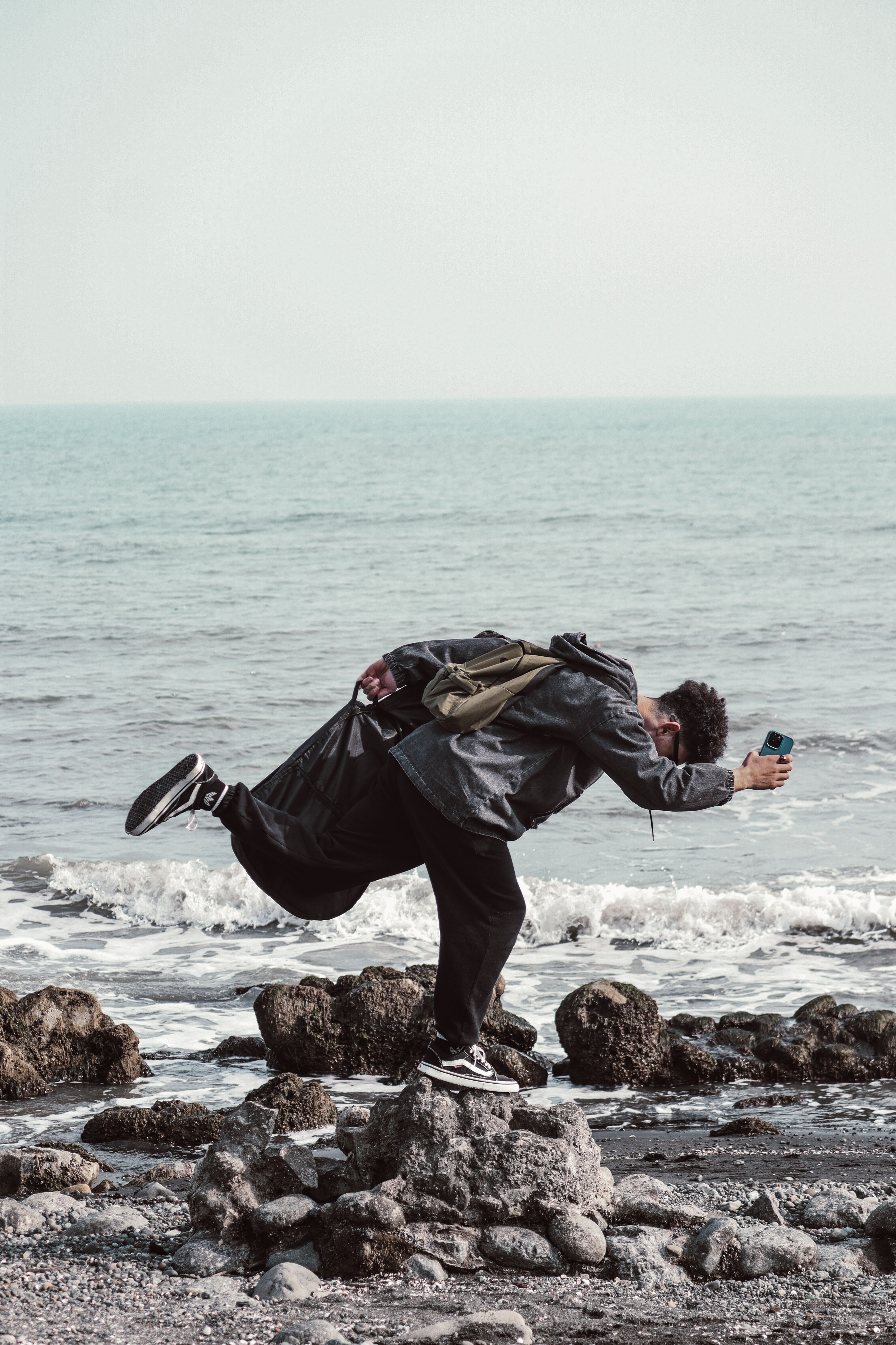 Man Posing on Stones on Sea Shore · Free Stock Photo