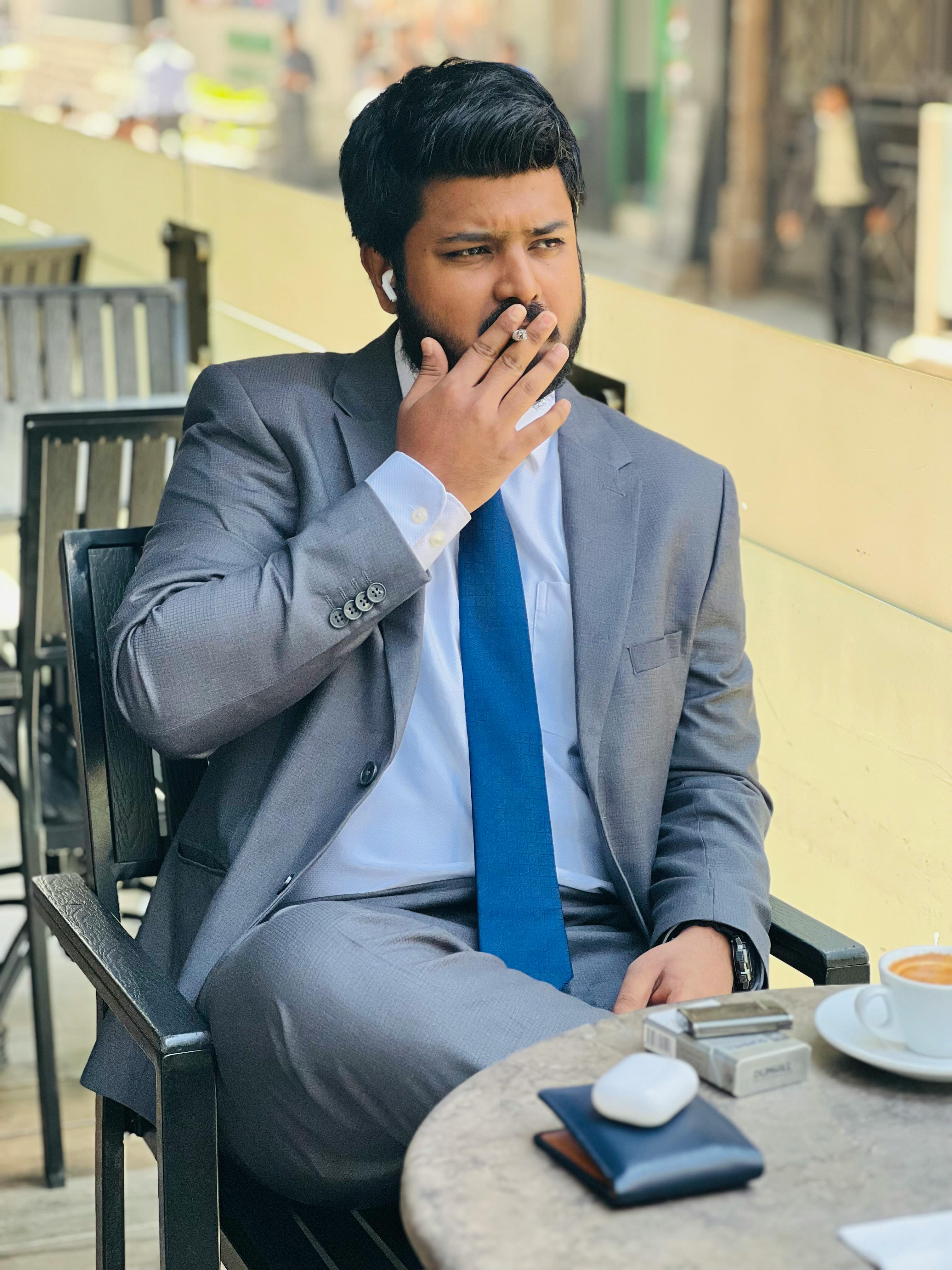 Man in a Suit Sitting and Smoking a Cigarette · Free Stock Photo