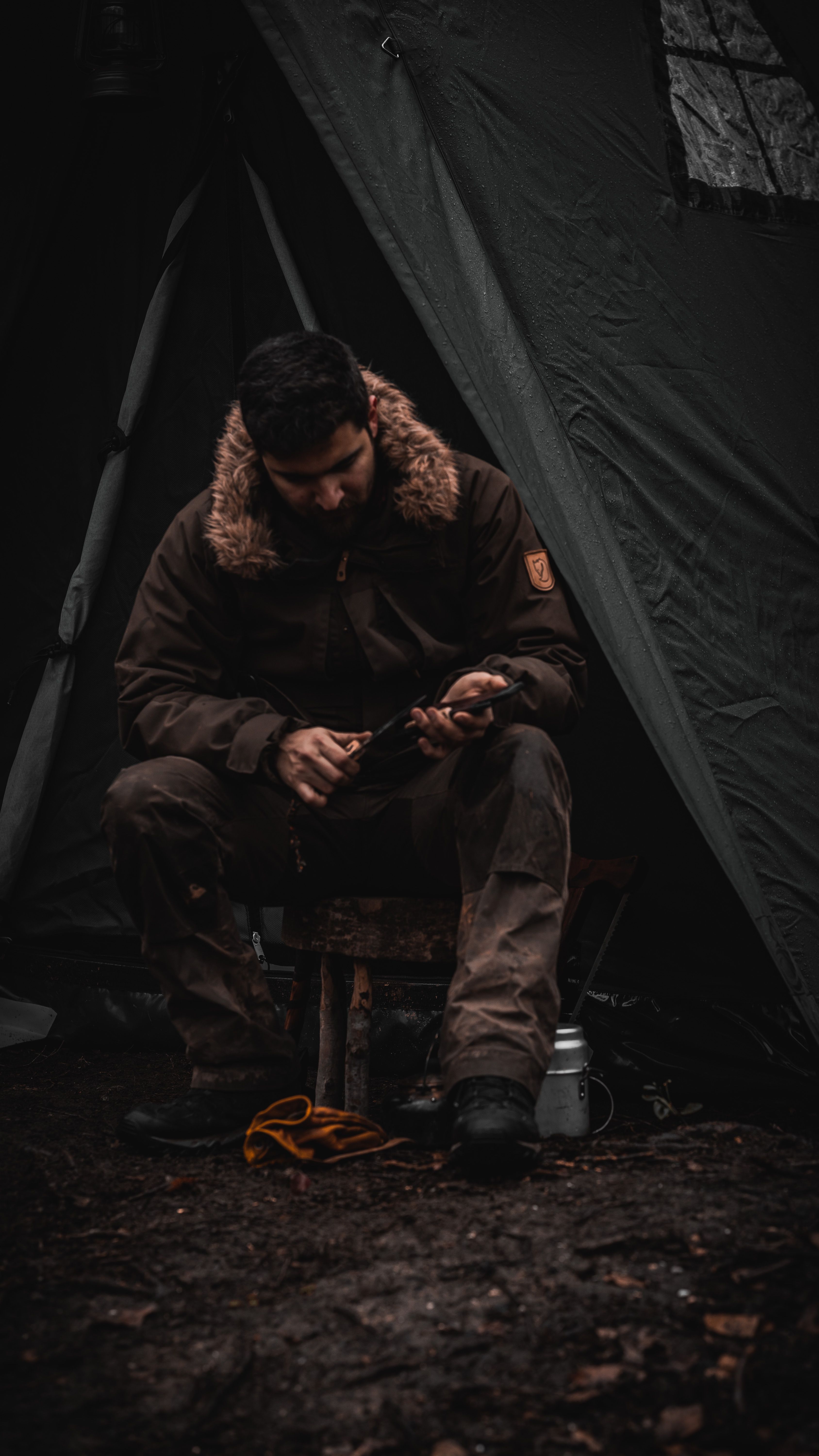 Man Sitting in front of Tent Holding Gun · Free Stock Photo