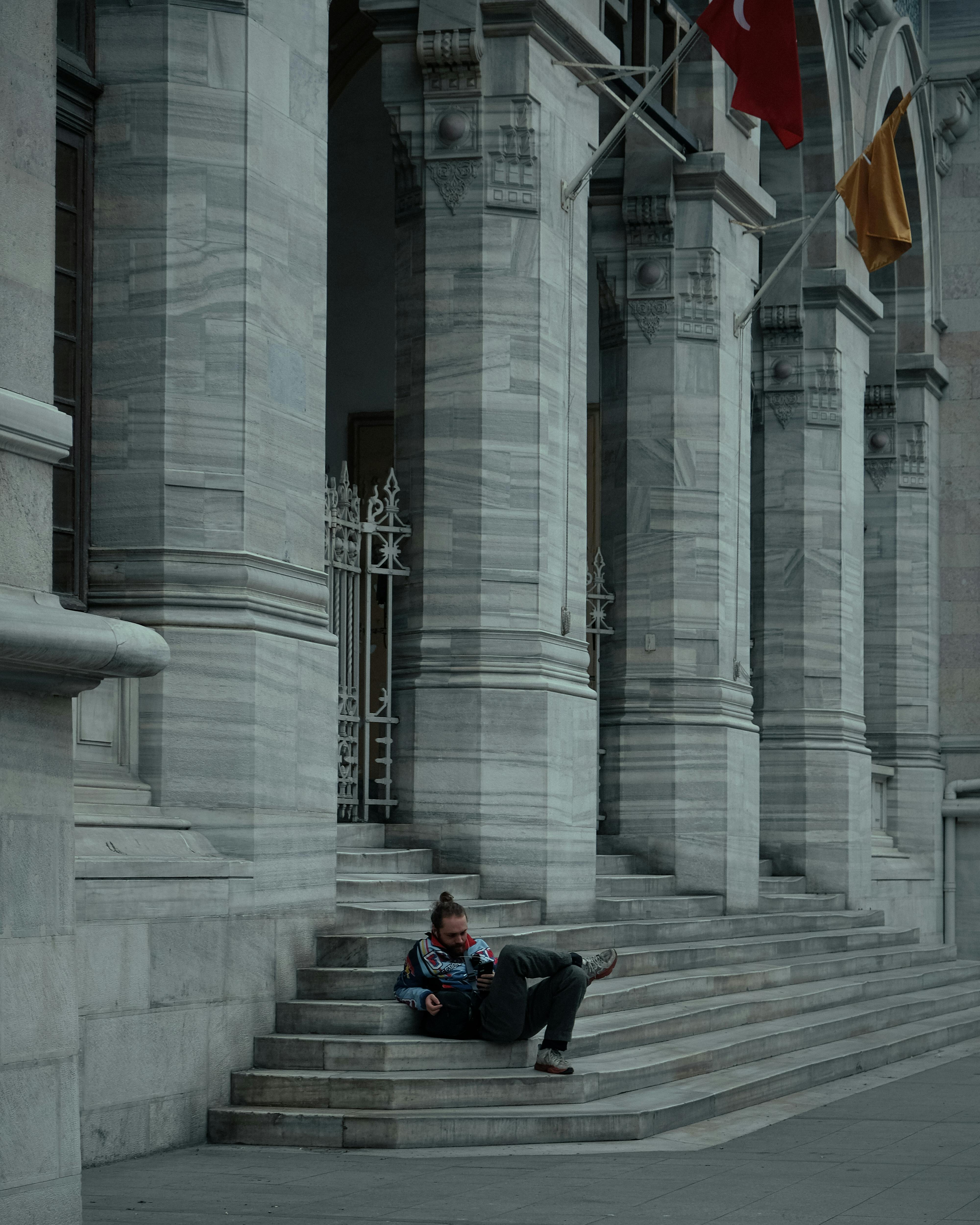 Man Sitting by Building Columns · Free Stock Photo