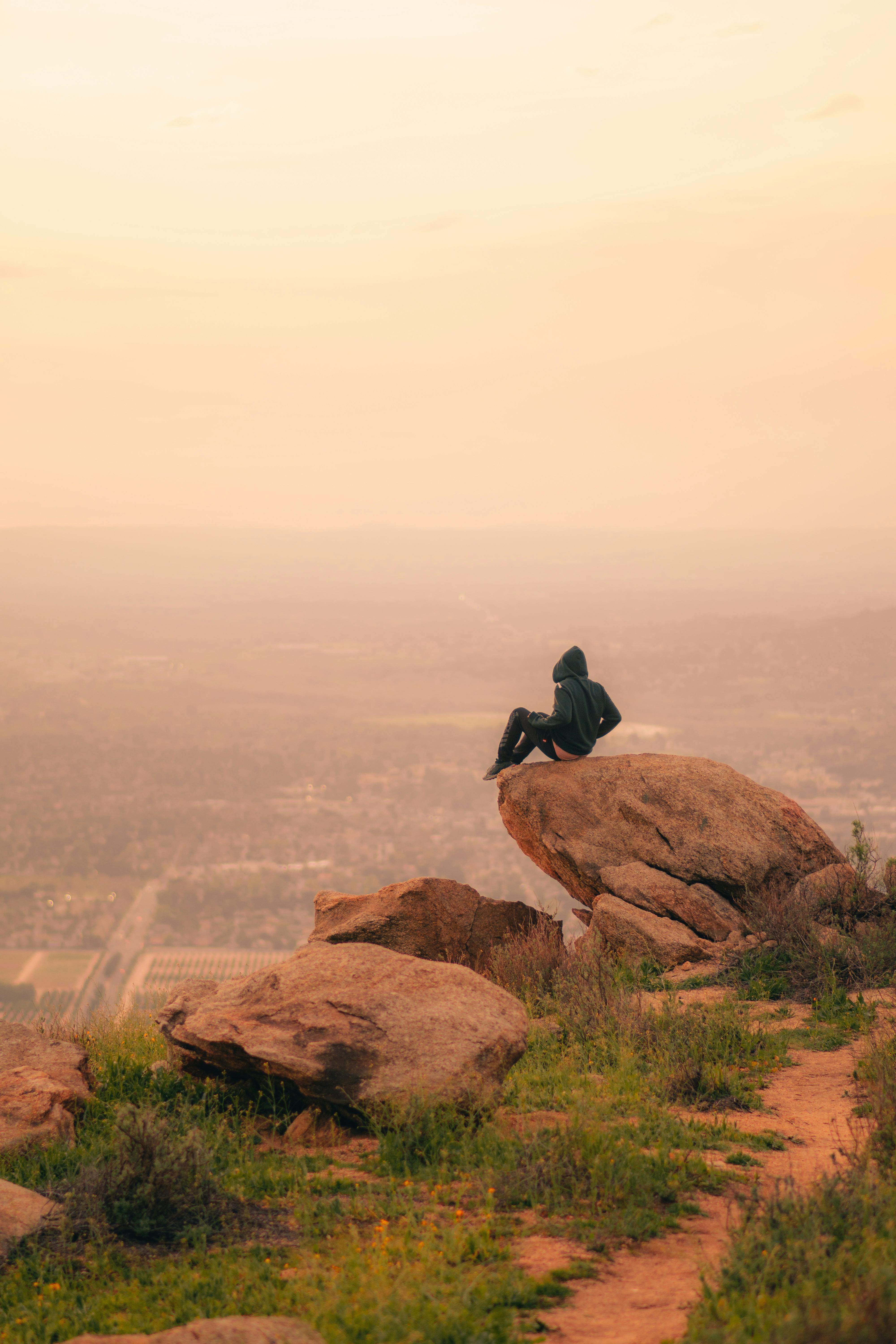 Person Sitting on Rocks over Plains at Dusk · Free Stock Photo