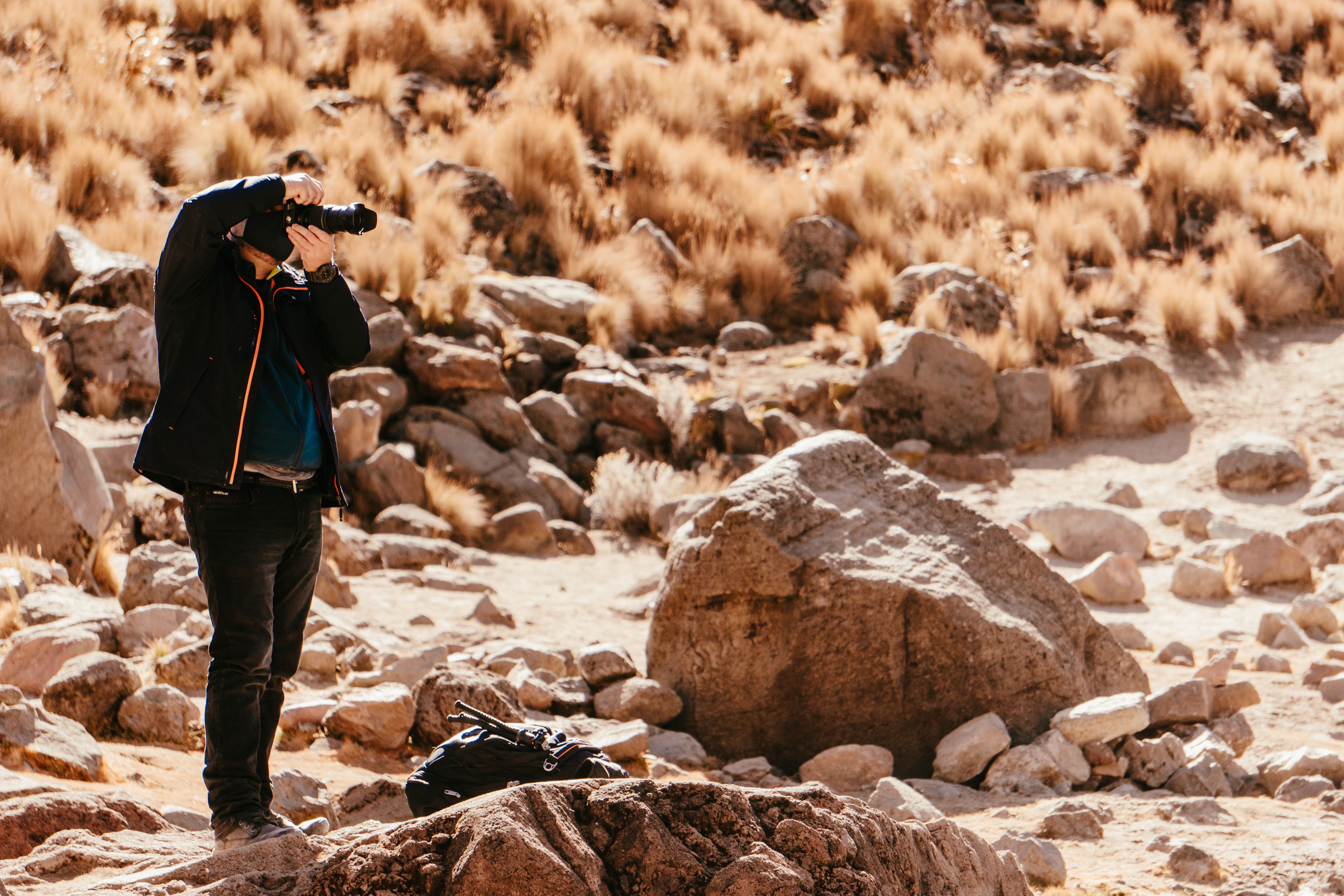 Man Standing on Rocks and Taking Pictures · Free Stock Photo