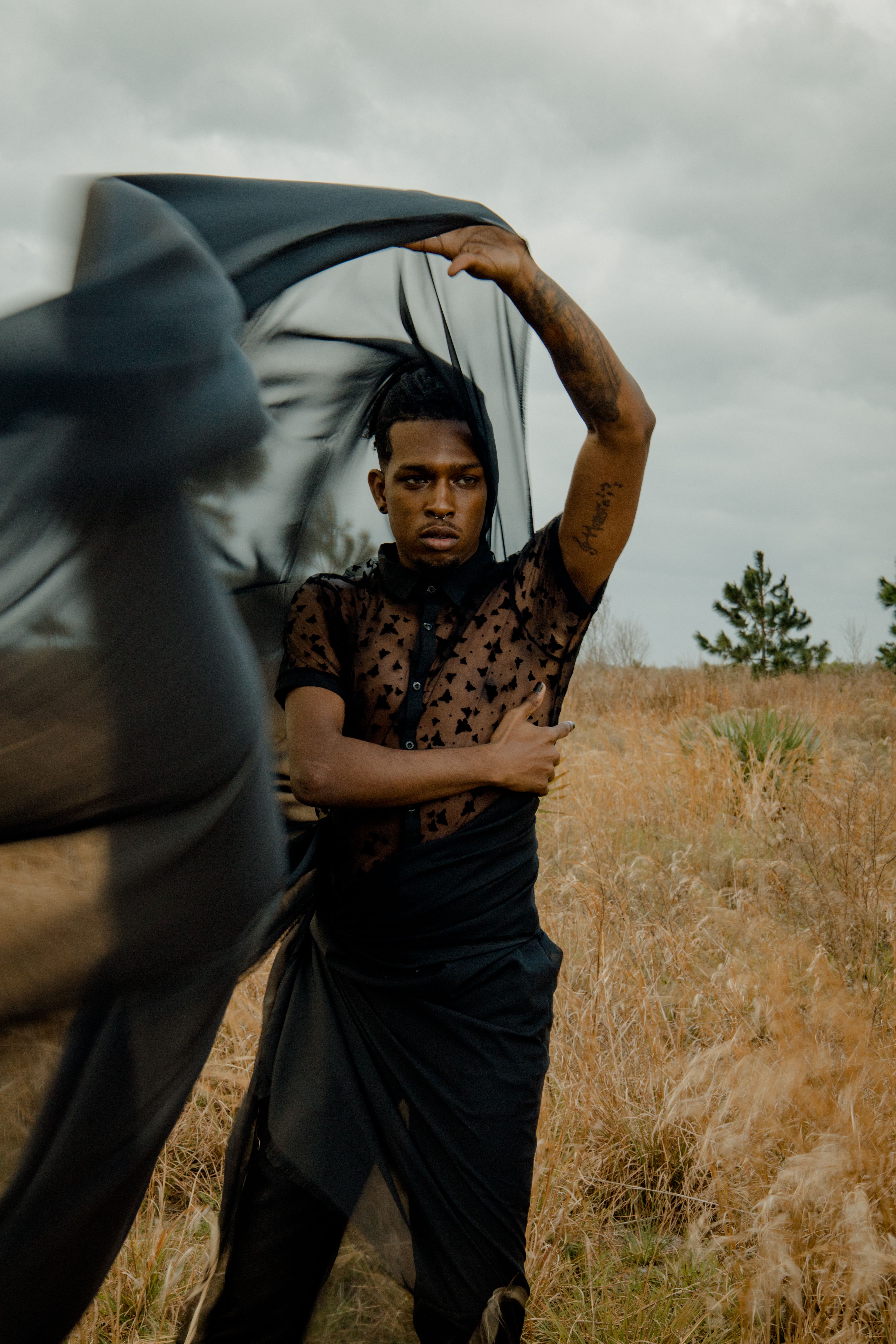 A black man is standing in a field with a black veil · Free Stock Photo