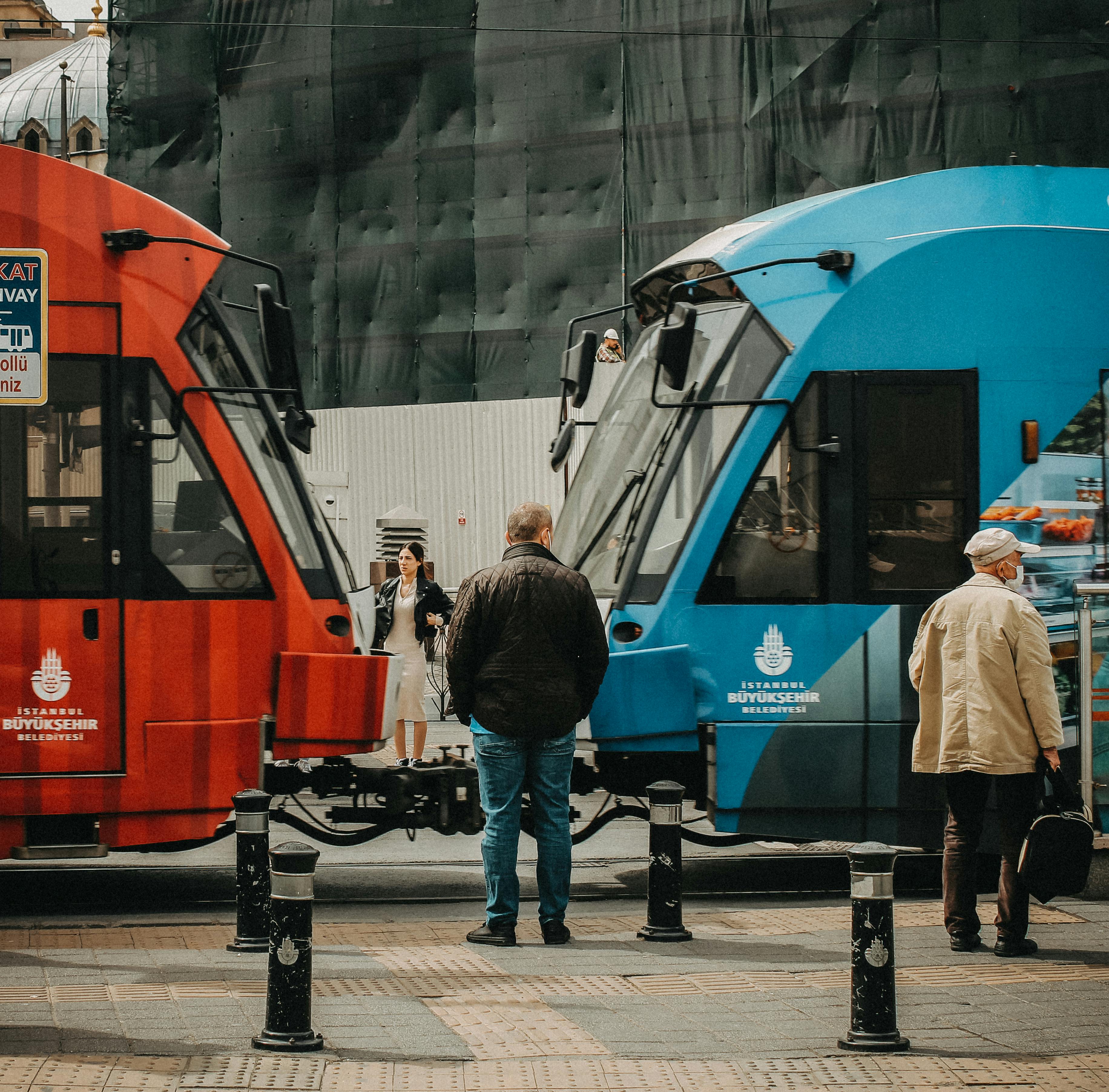 People in Front of Red and Blue Trams · Free Stock Photo