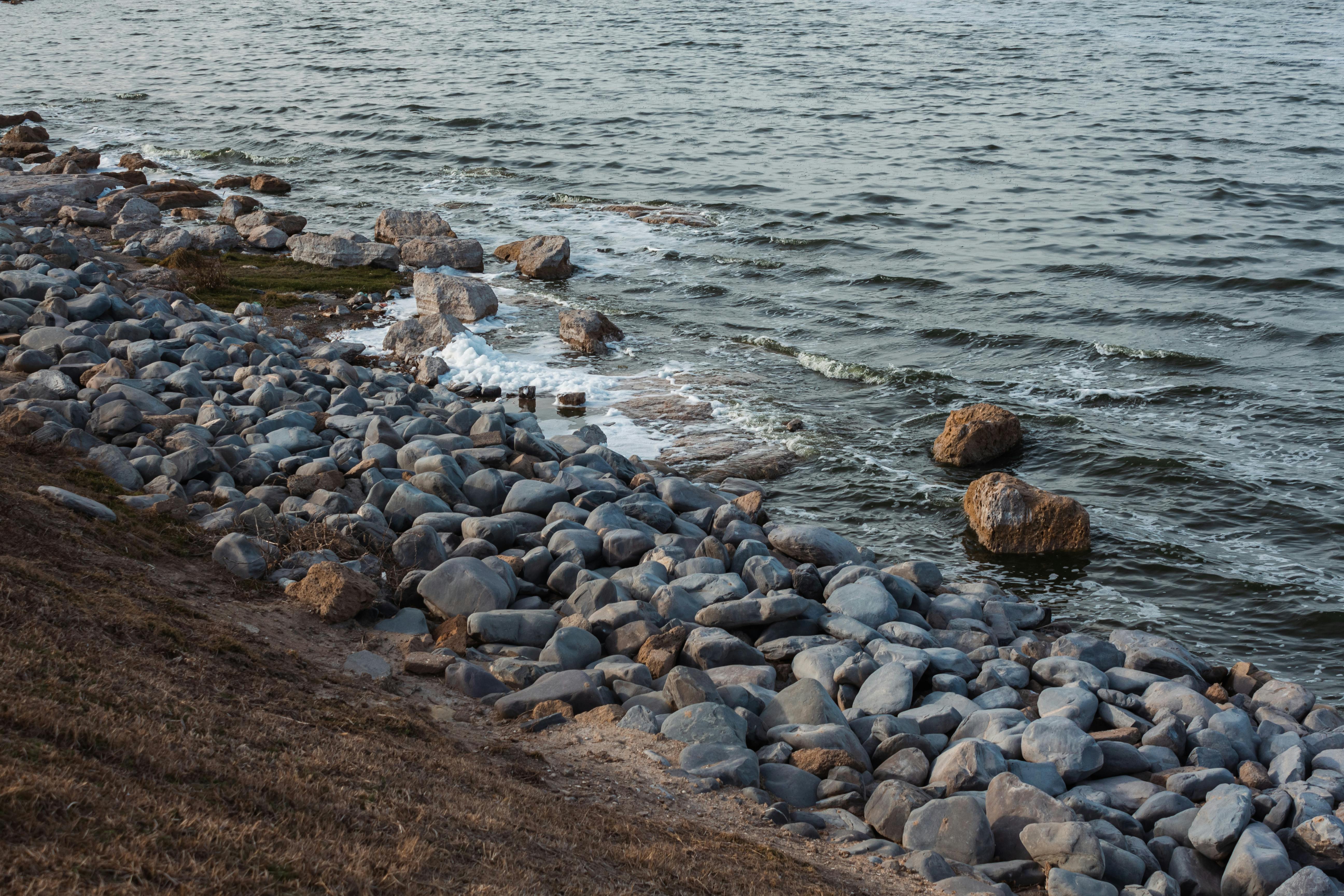 Round Rocks Piling up on Sea Shore · Free Stock Photo