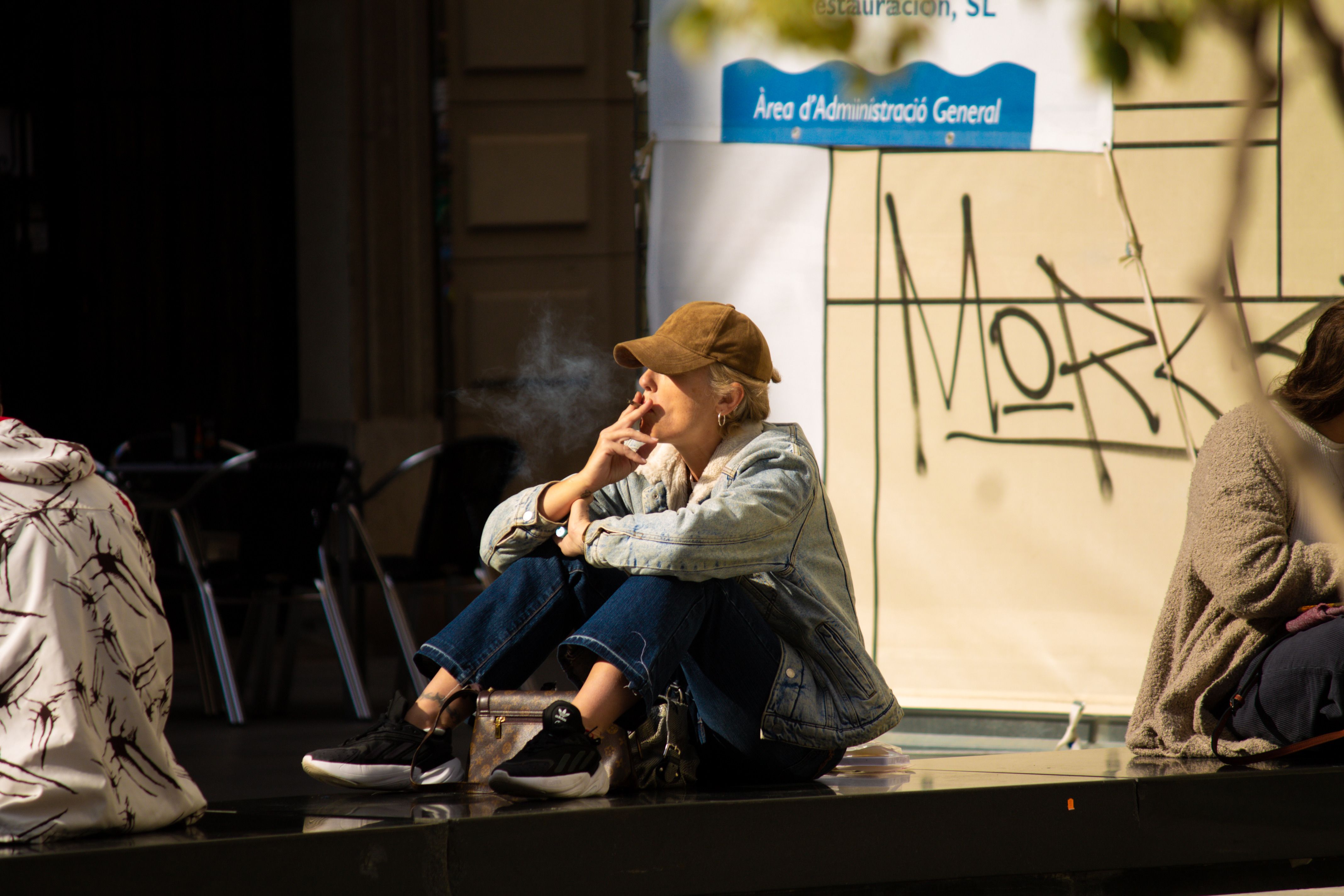 Woman in Cap Sitting and Smoking Cigarette · Free Stock Photo