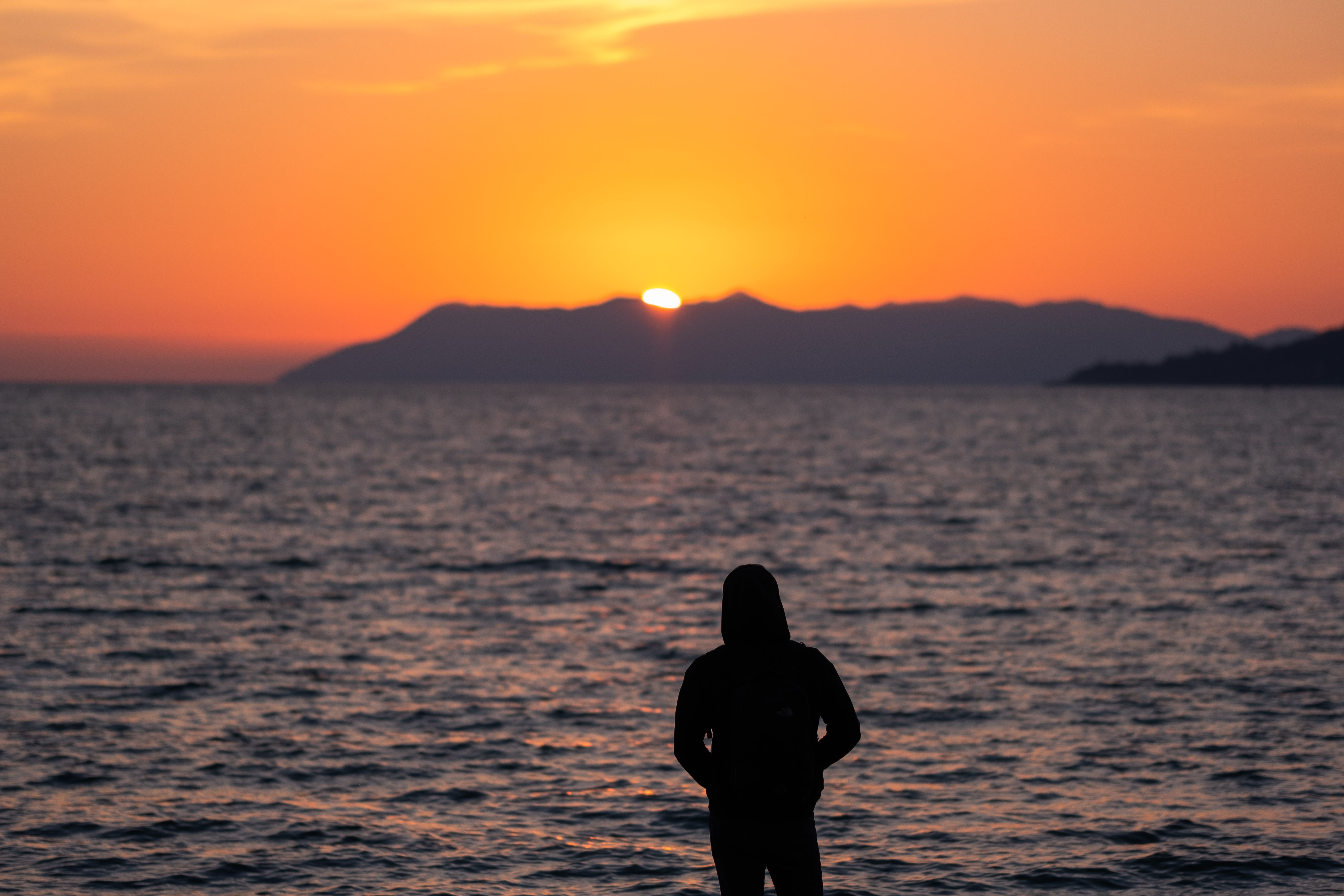 Silhouette of a Lone Person Looking at the Sea at Sunset · Free Stock Photo