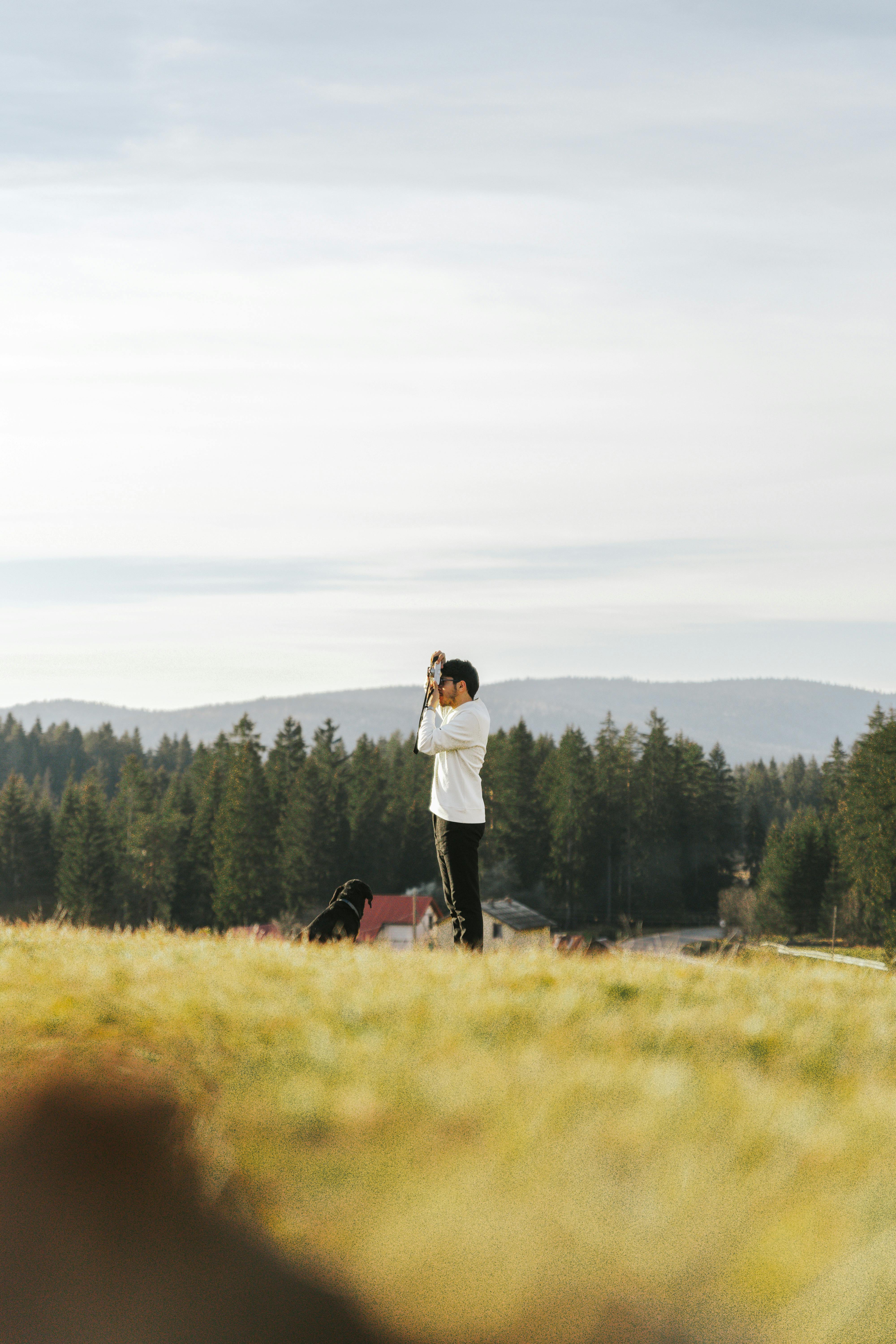Man Standing in a Grass Field and Photographing Landscape · Free Stock ...