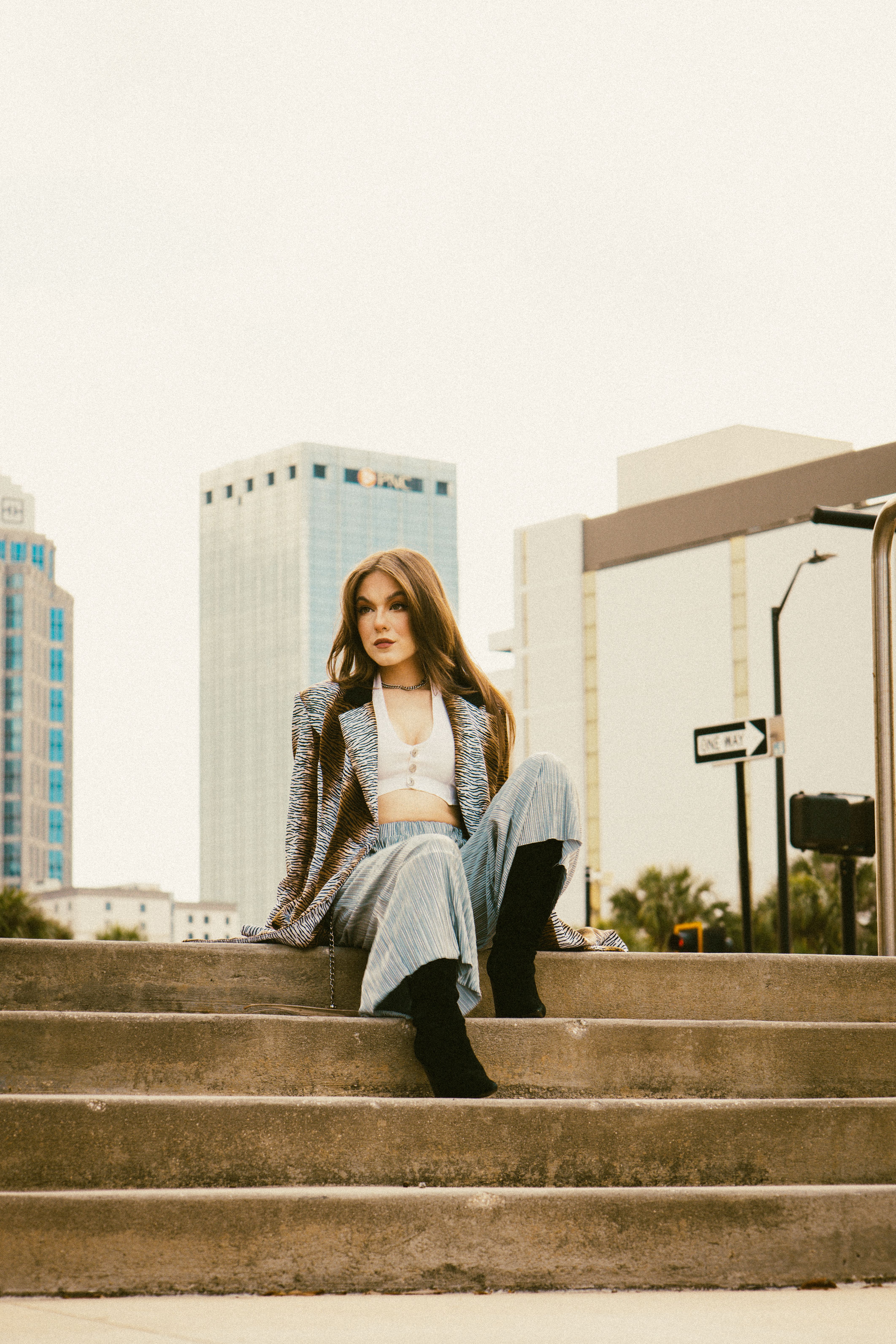 A woman sitting on some steps in front of a city · Free Stock Photo