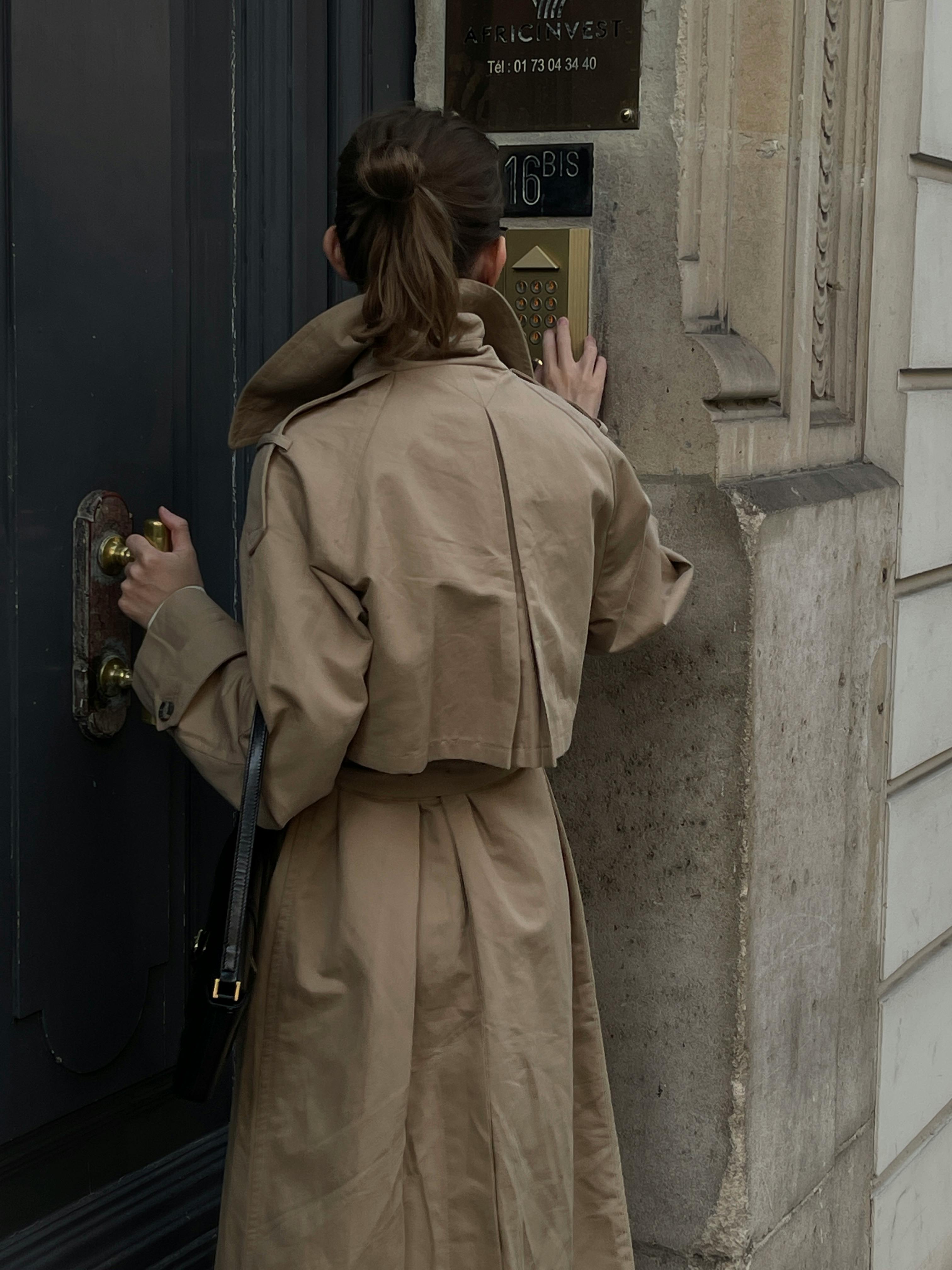 Back View of a Woman in a Trench Coat Opening the Door to a Tenement ...