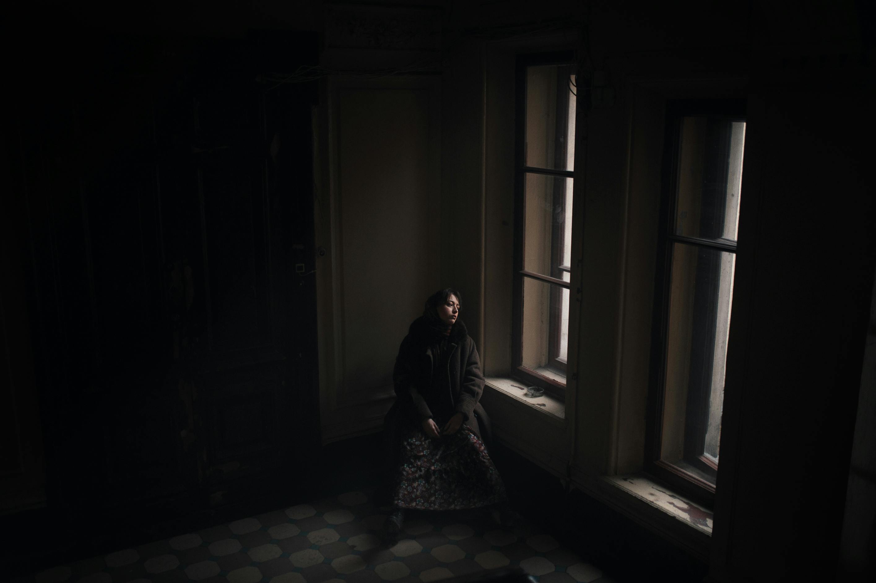 Sad Woman in Warm Clothing Sitting in an Empty Room · Free Stock Photo